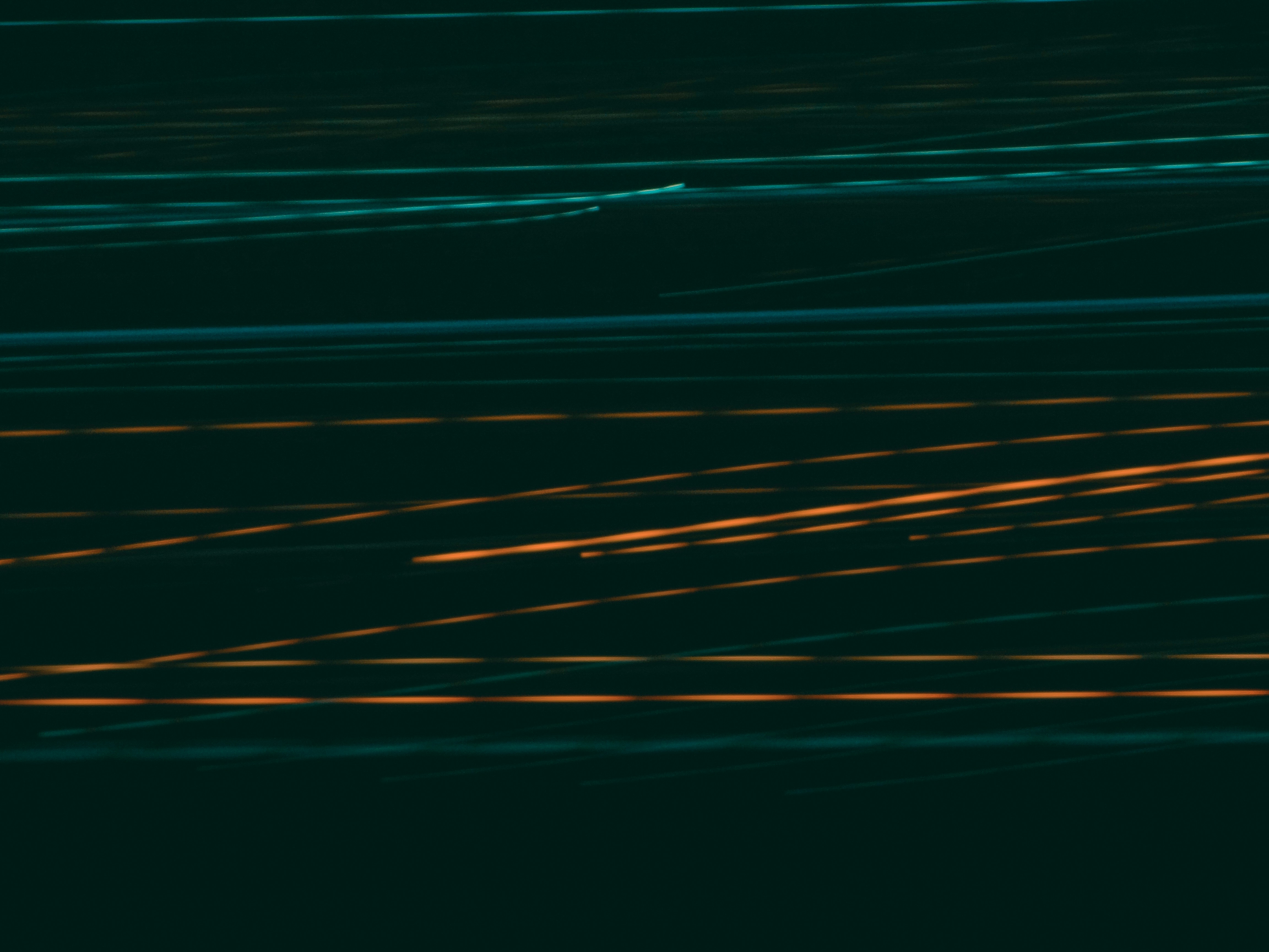 Blurred streaks of orange and teal light against a dark background.