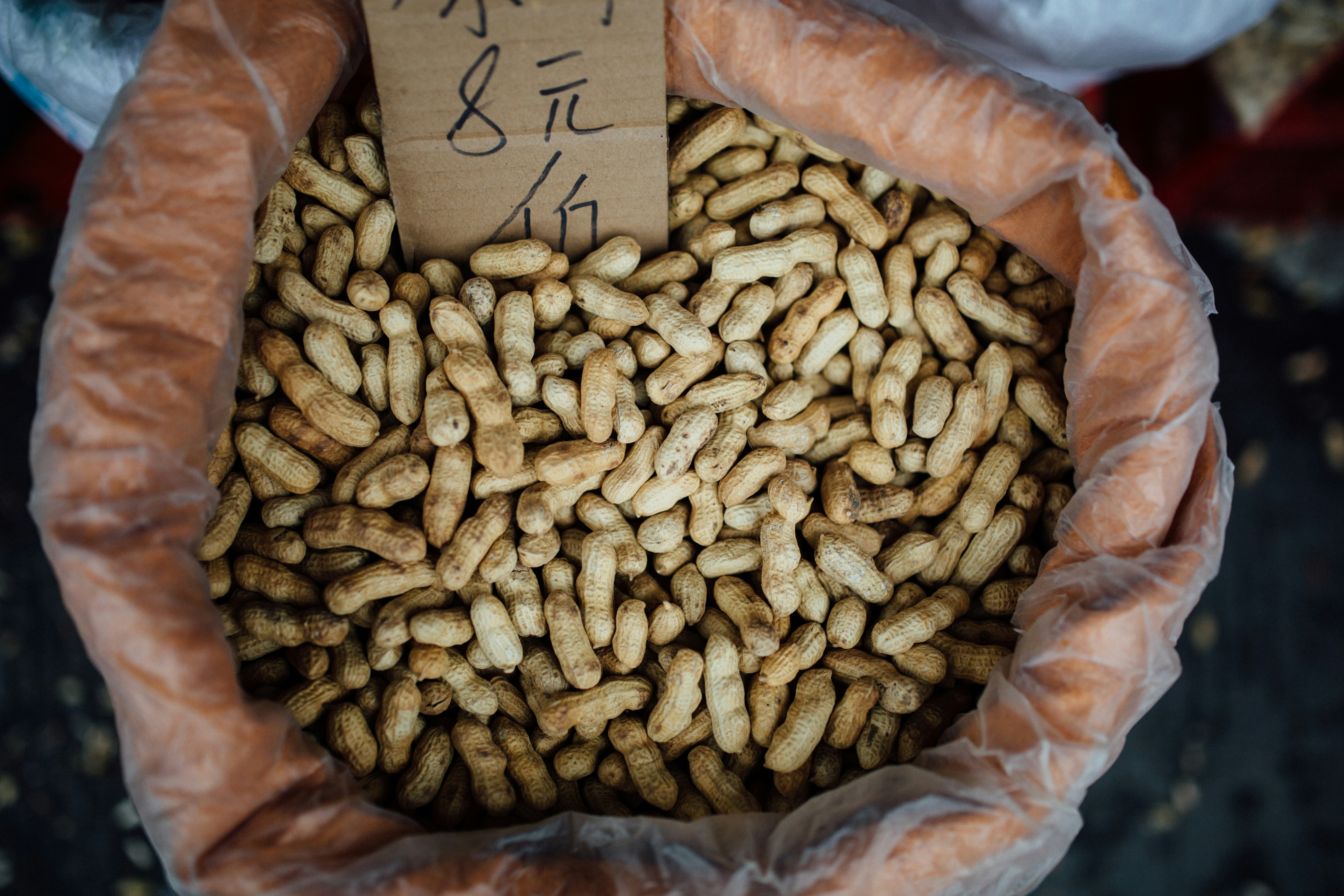 Bag of puffed corn pellets in a burlap sack at a market stall; close-up showing texture and earthy tones.