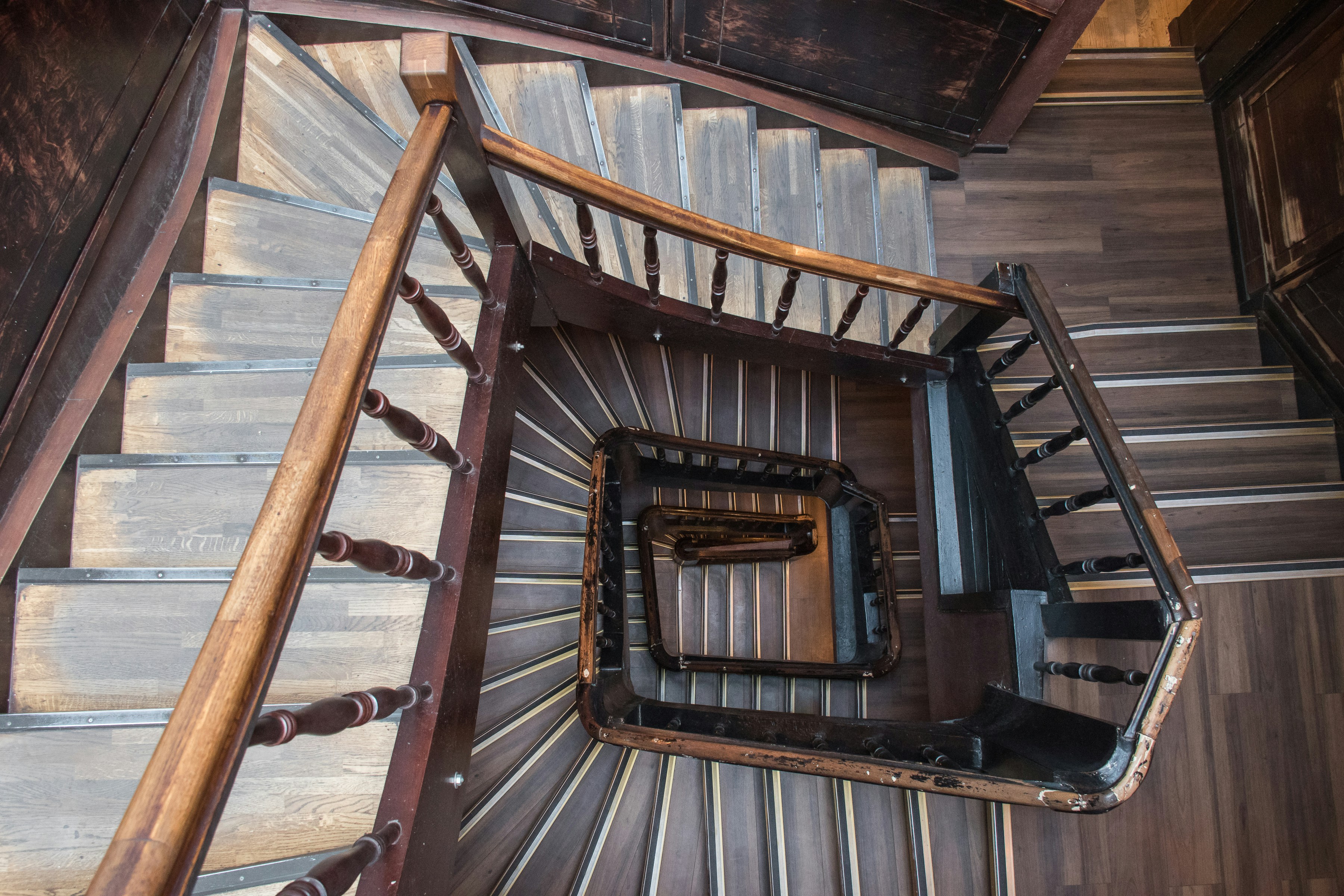 Intricate spiral staircase showcasing wooden railings and contrasting flooring patterns.