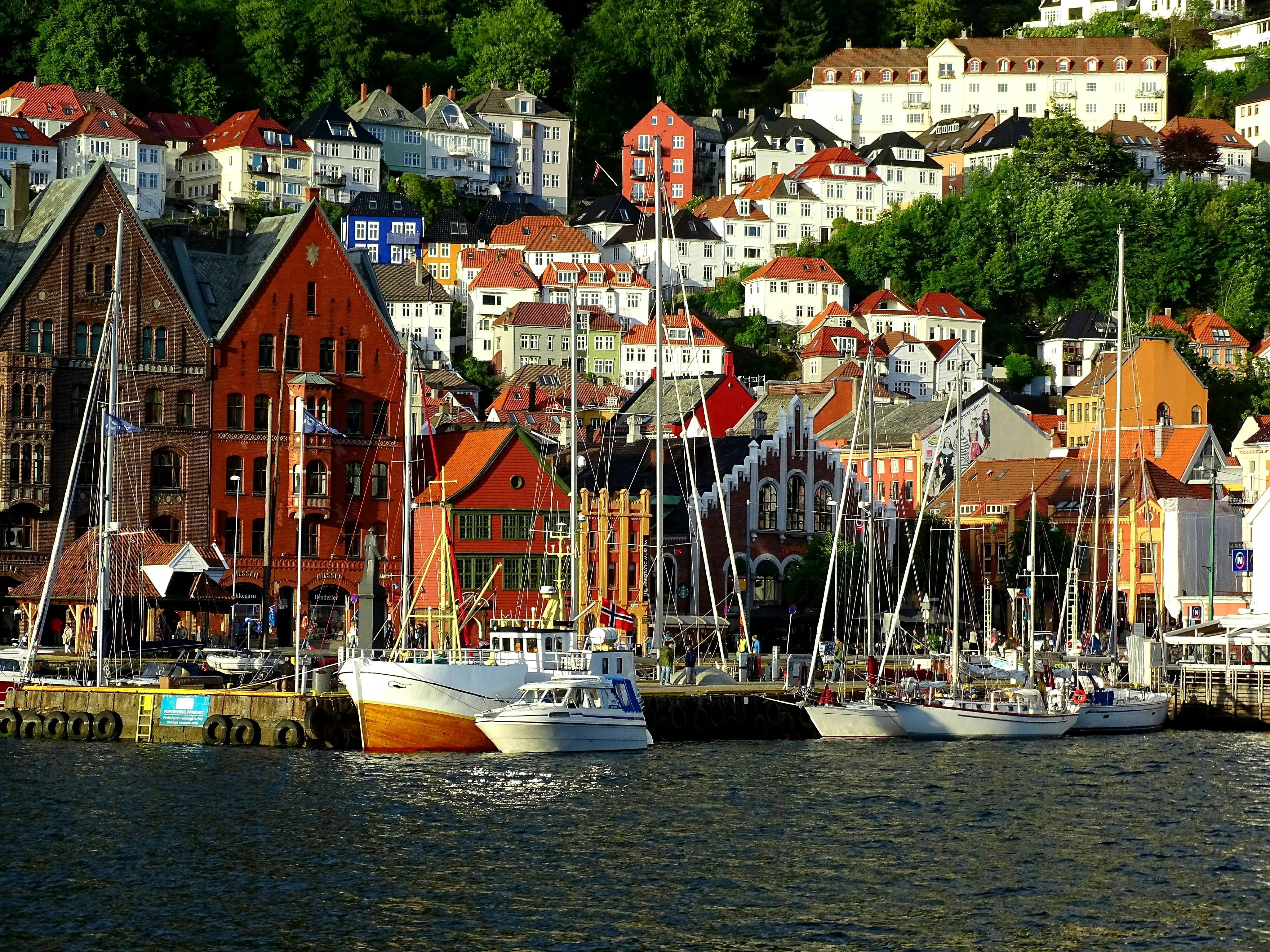 Colorful buildings line a waterfront with sailboats docked in the foreground.