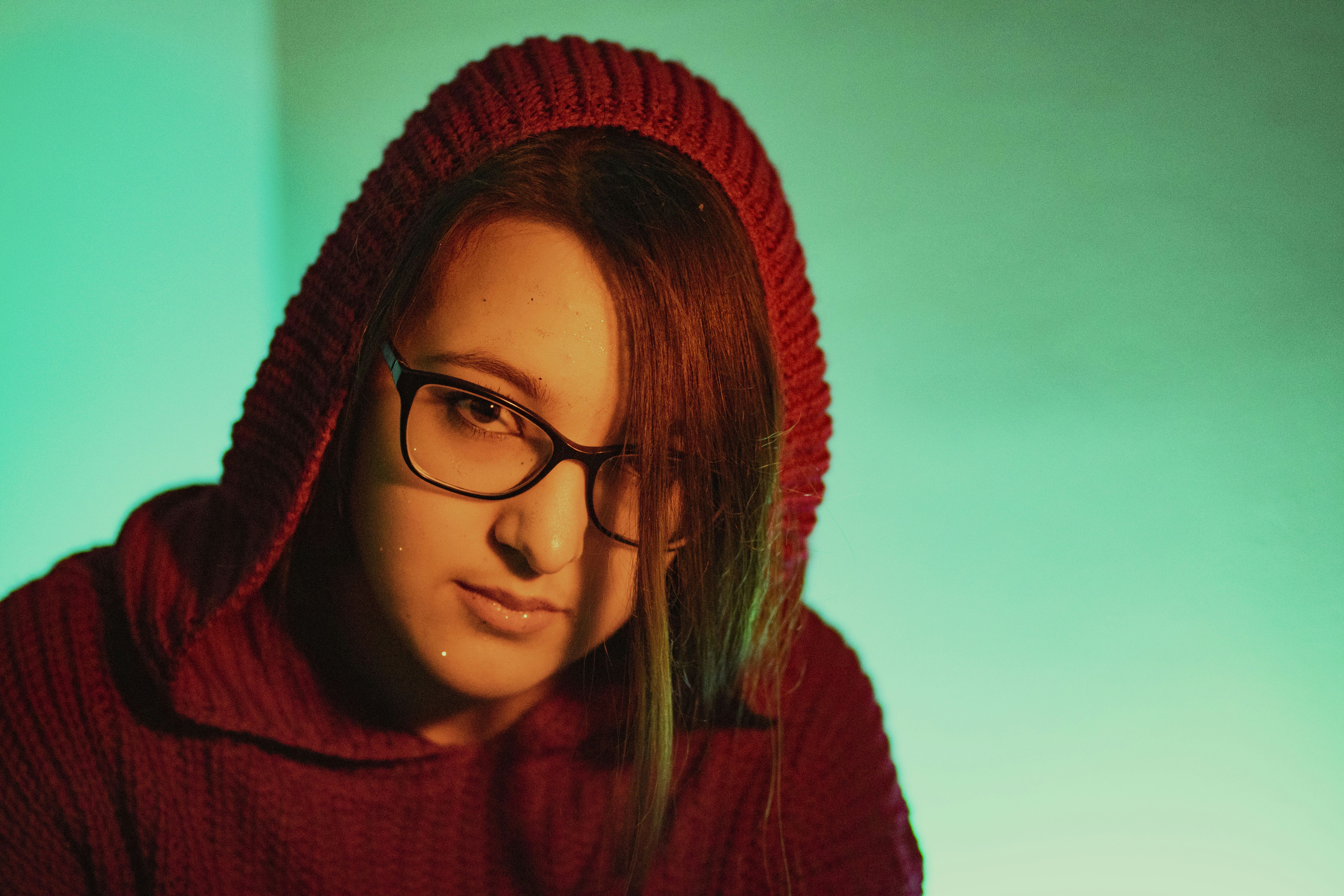 Teal Backlight Portrait: A Quiet Gaze in a Crimson Knit Hoodie