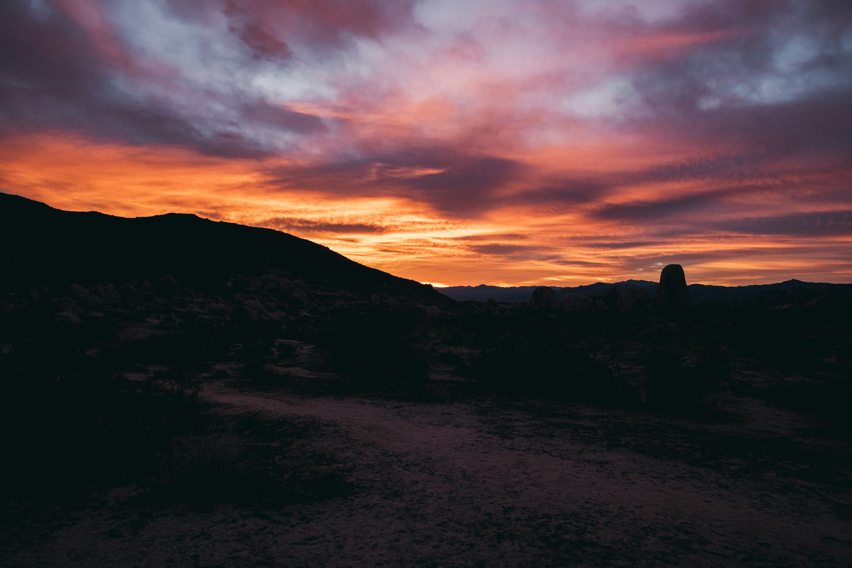 Silhouetted mountains beneath a vibrant, multi-colored sunset sky.