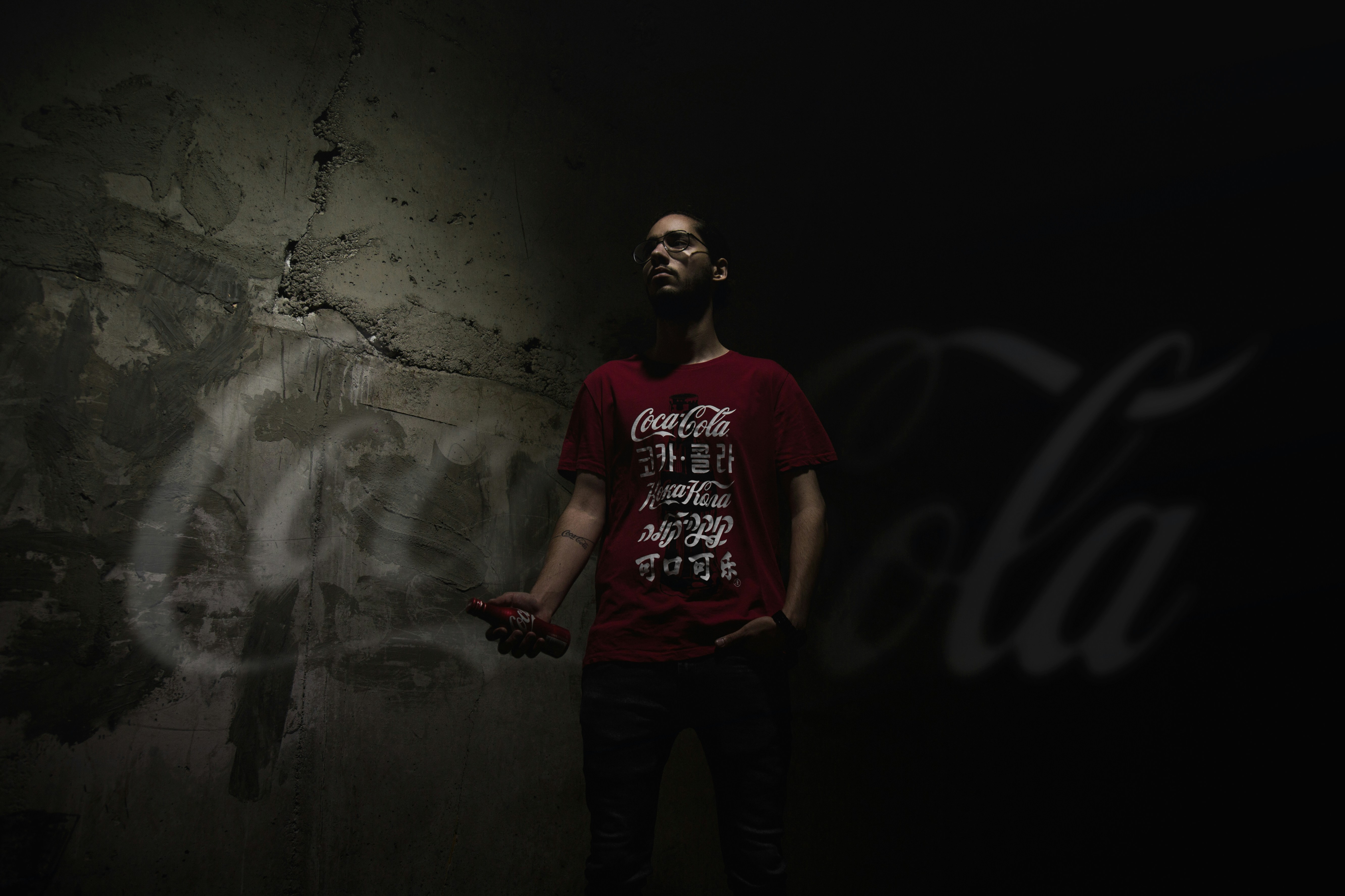 Man wearing red Coca-cola shirt standing near wall painted with white ...