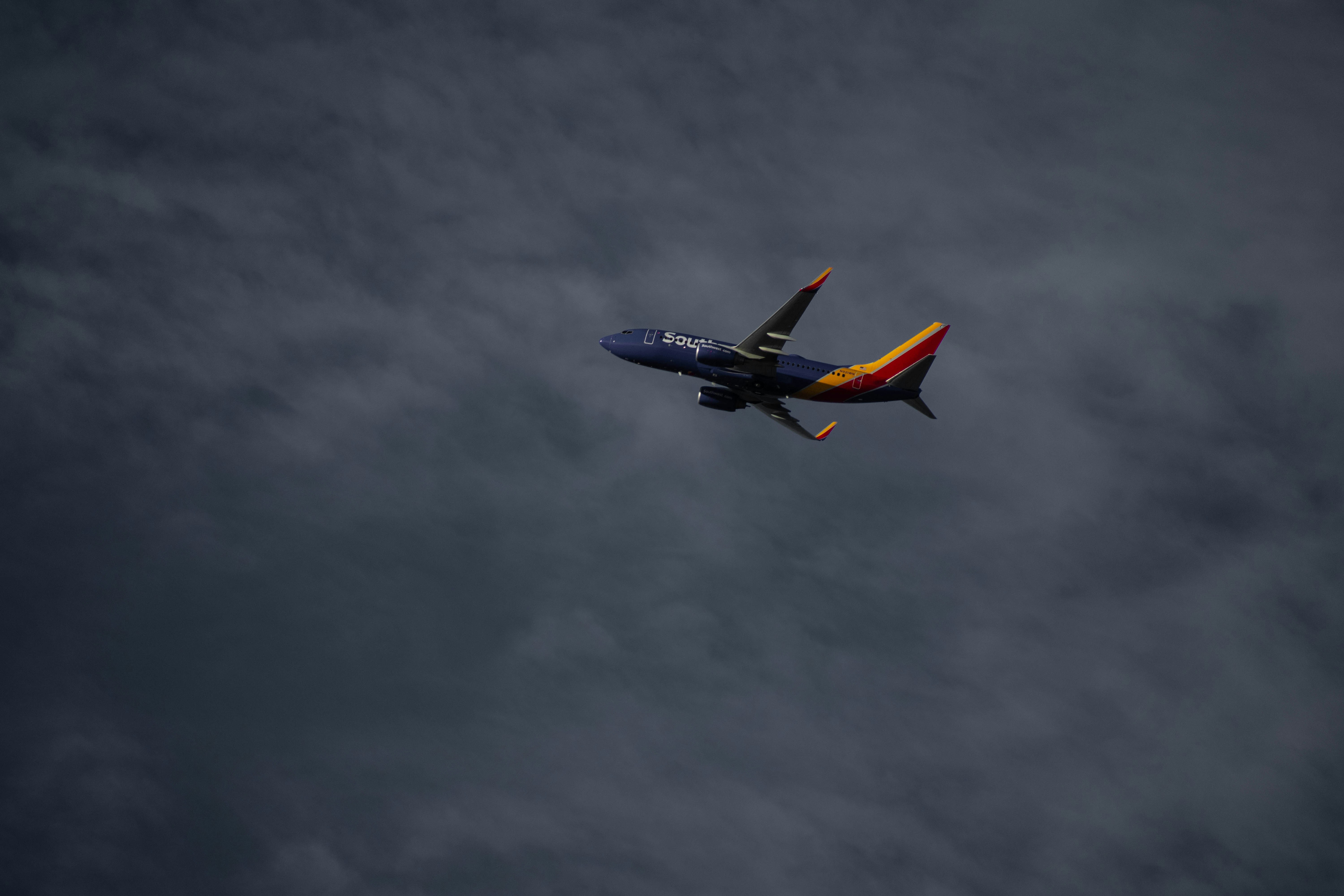 Commercial airplane flying against a backdrop of dramatic, textured clouds.