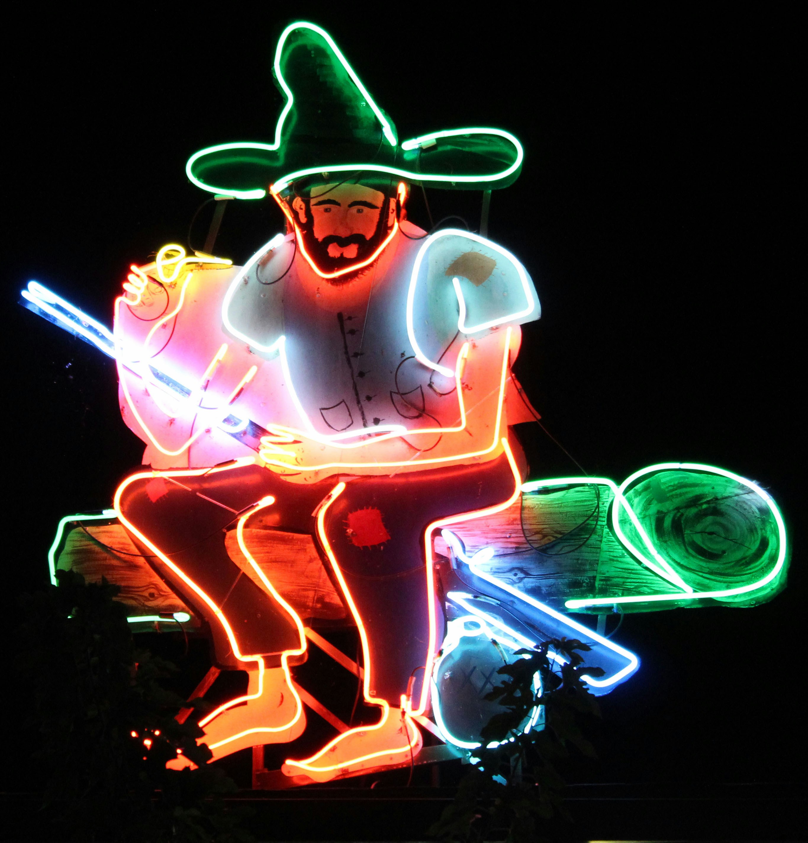 man sitting on log lighted artwork
