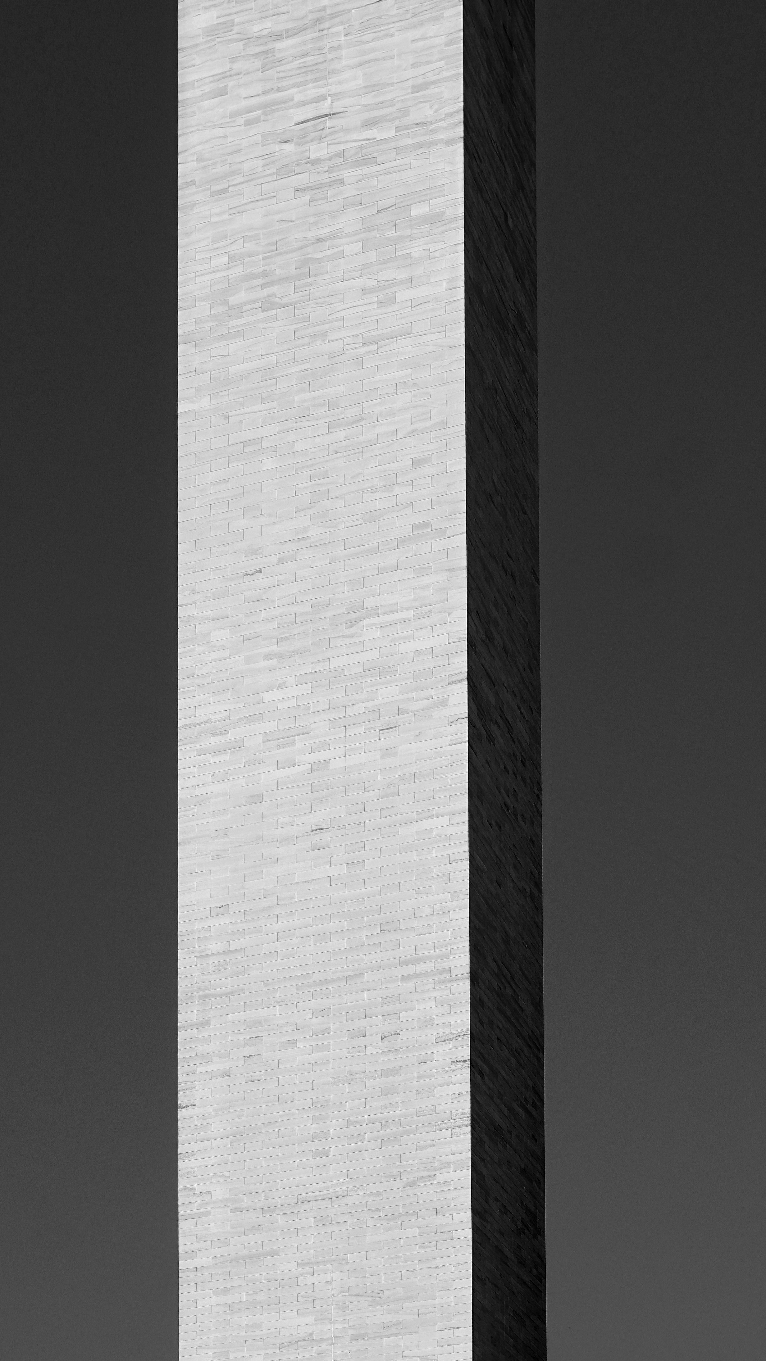 A tall, monochromatic monument rising starkly against a gradient sky, showcasing textured stonework that emphasizes its architectural grandeur.