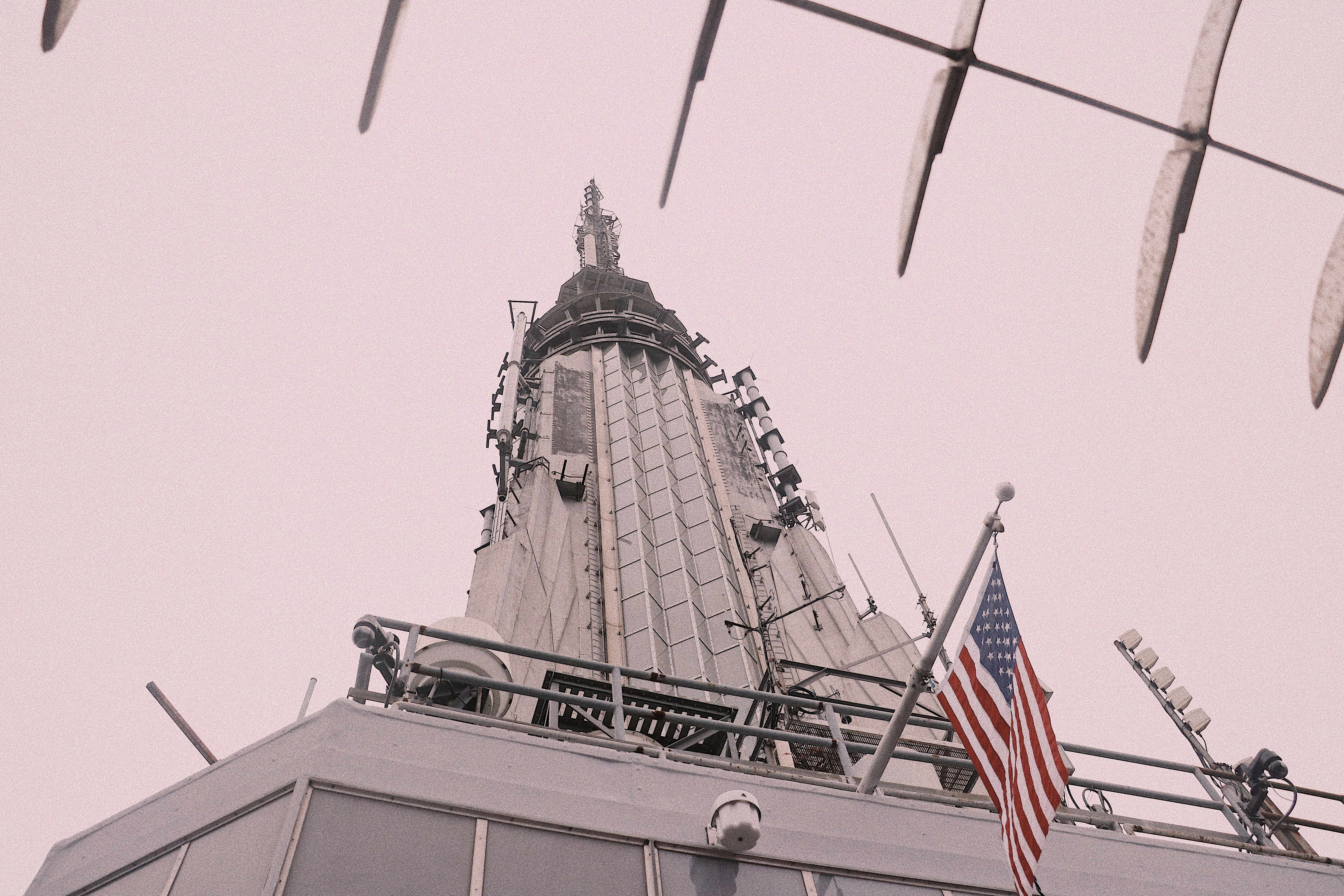 Spire Above the Rooftop: Flag at the Edge of a Pink Sky