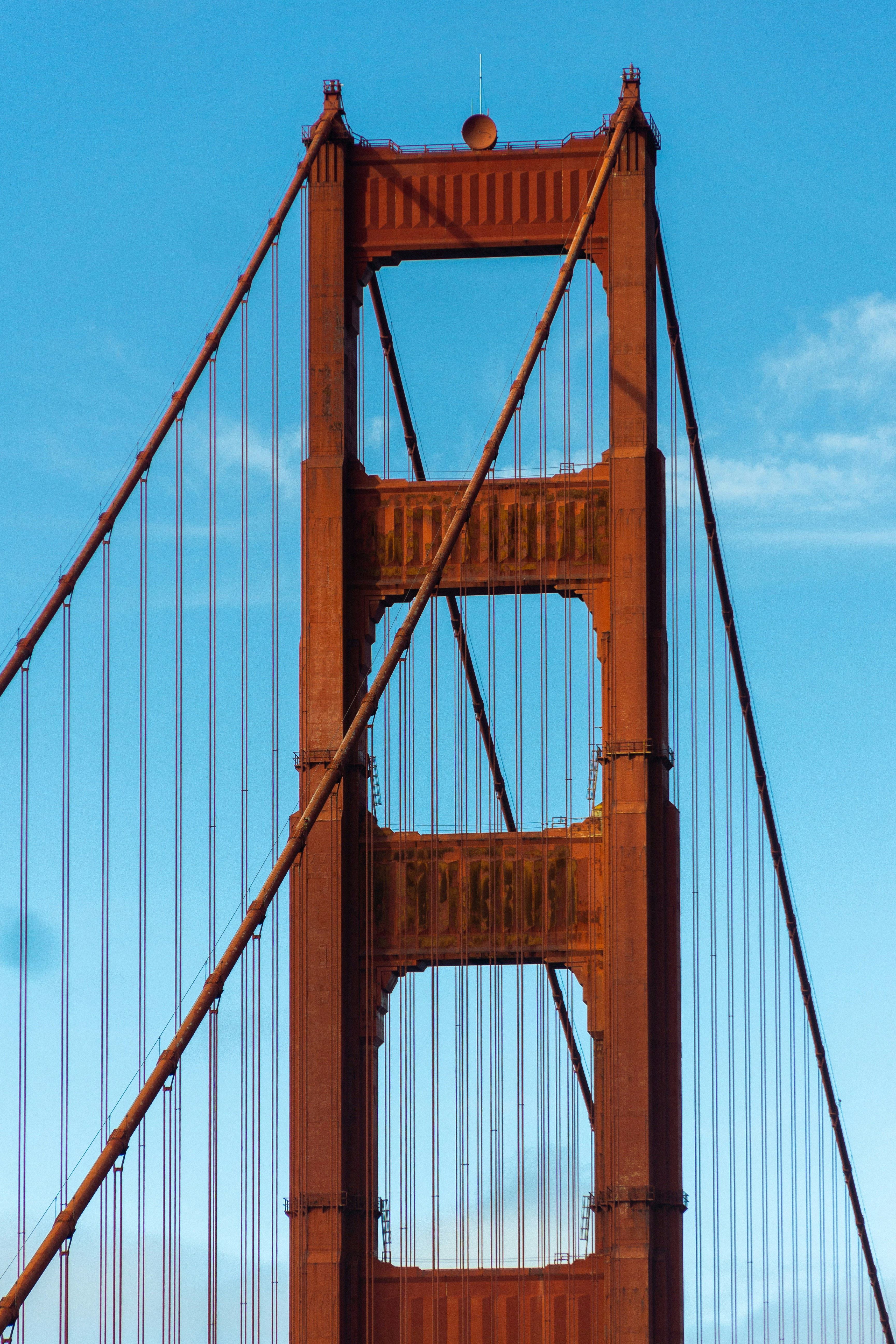 The towering structure of the Golden Gate Bridge's main tower against a clear blue sky, showcasing its iconic design and engineering prowess.