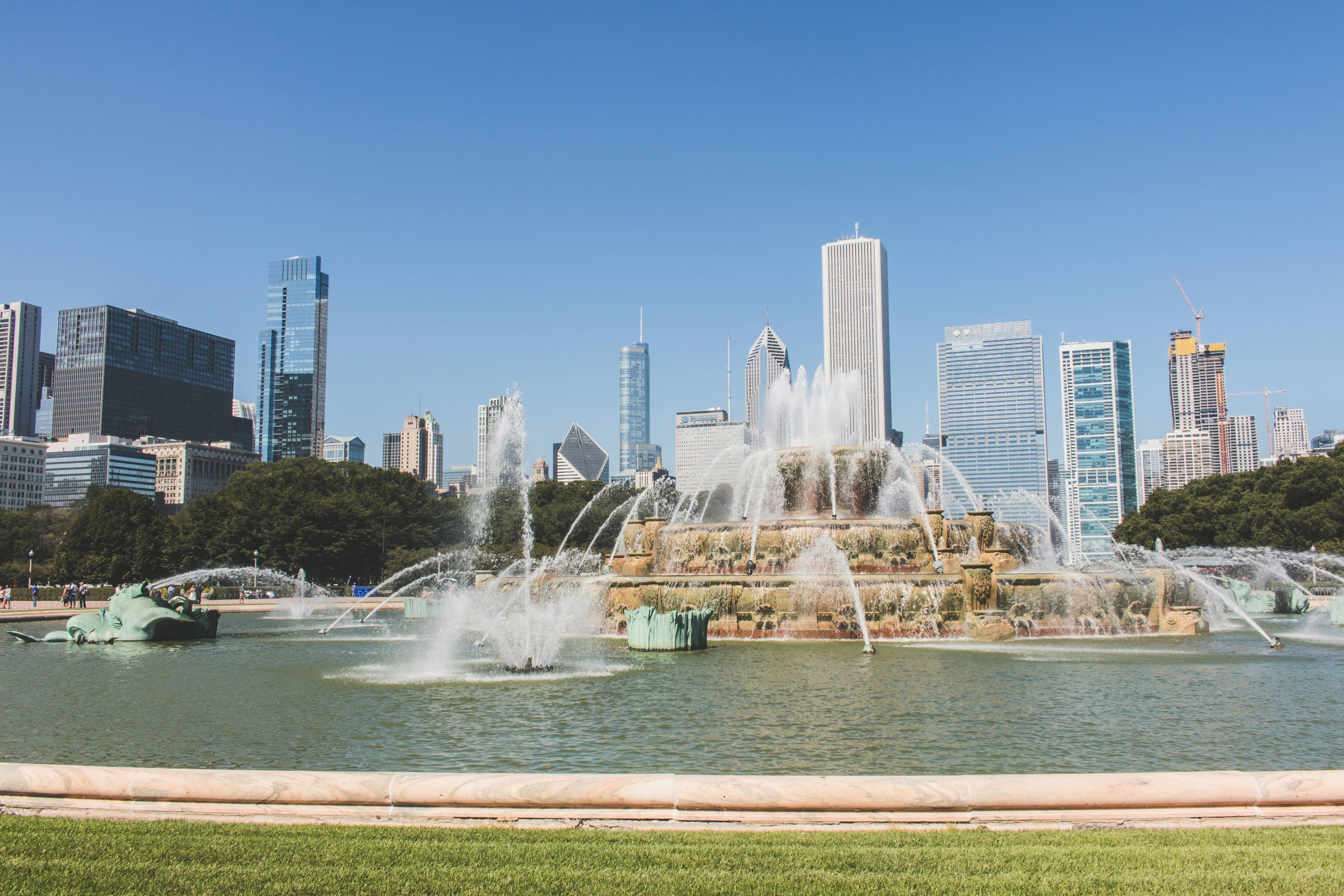 Buckingham Fountain in Chicago, with jets of water spraying against a backdrop of modern skyscrapers and clear blue skies.