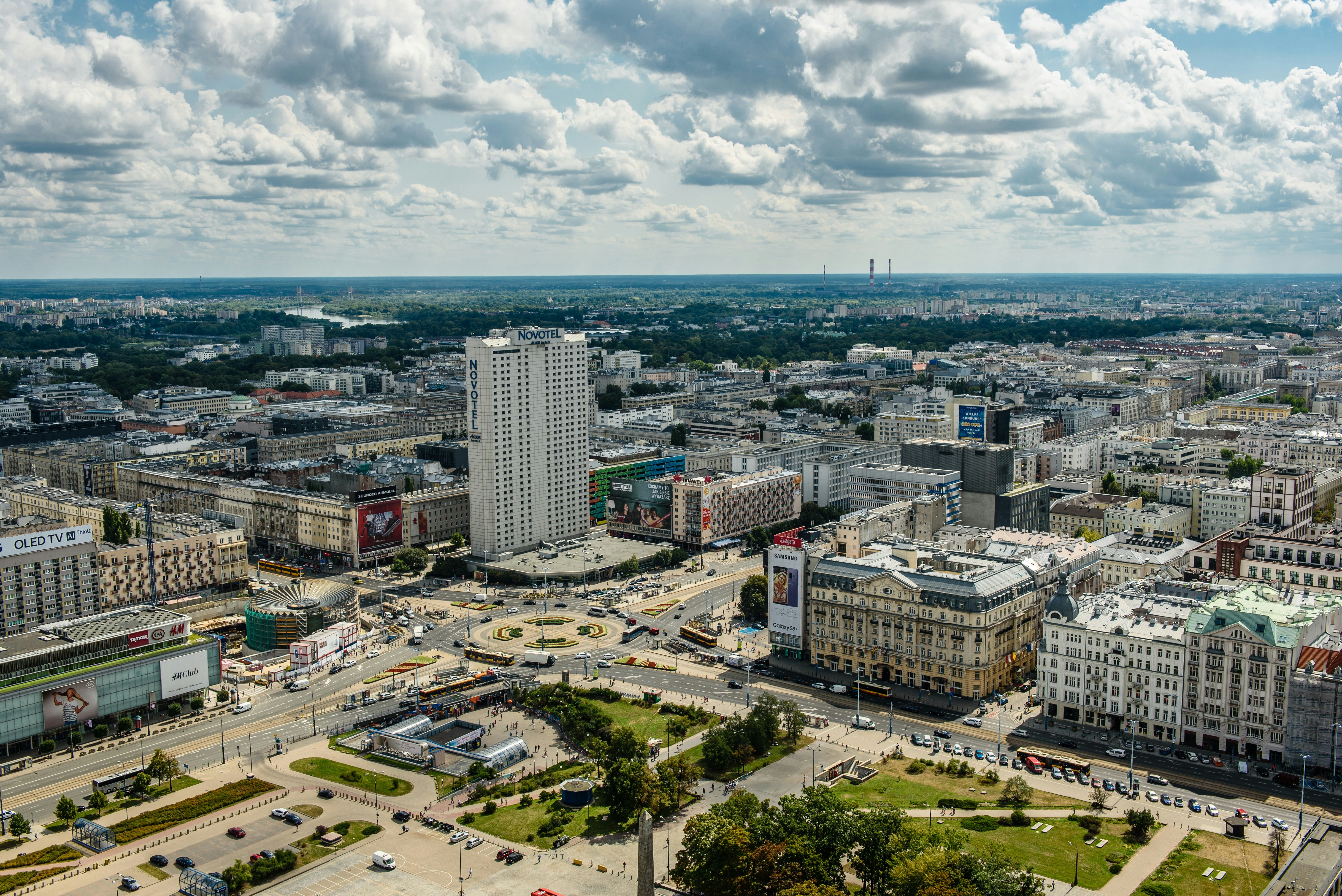 Expansive cityscape with modern buildings under a dynamic cloud-filled sky.