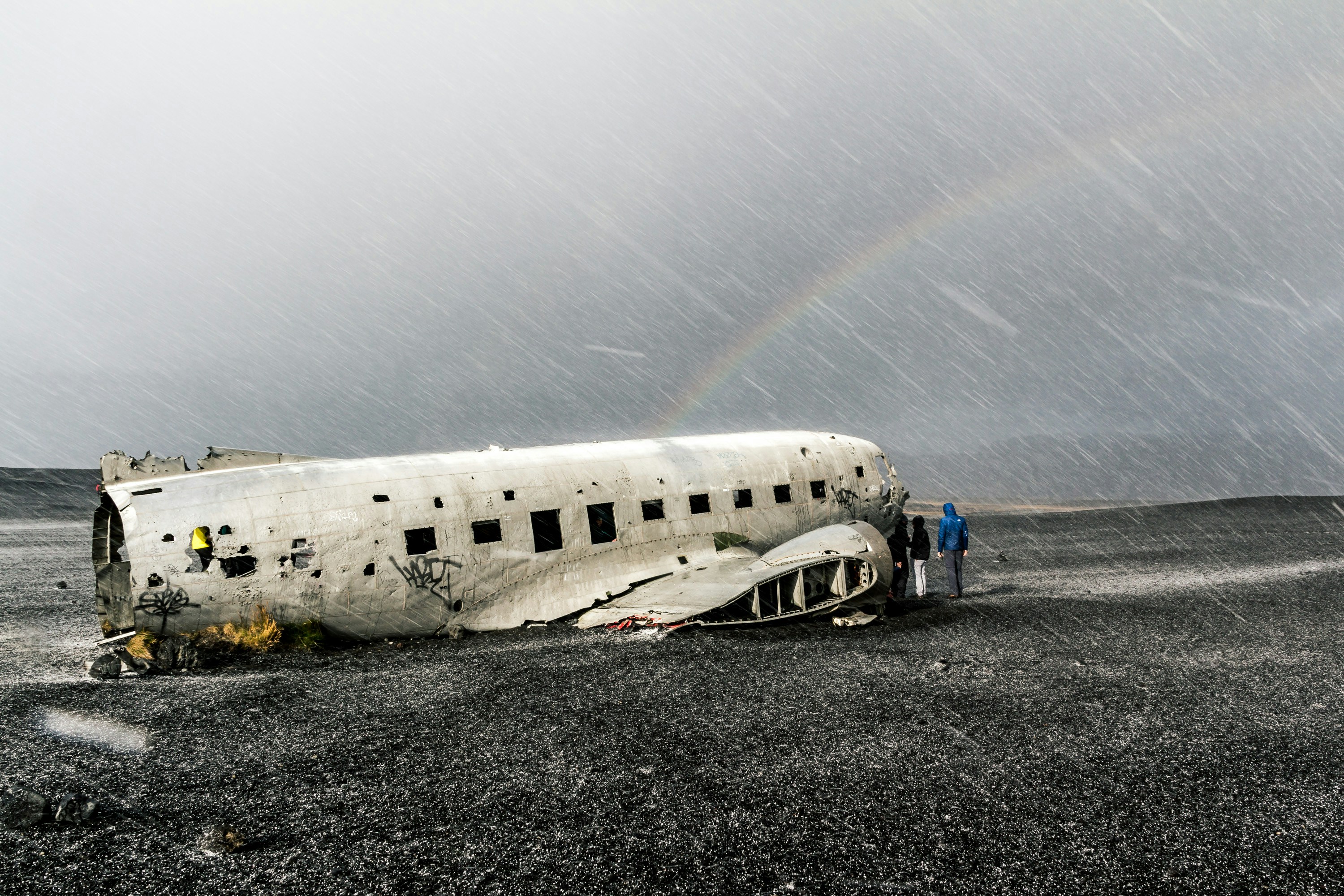 2 people standing near white broken plane fuselage
