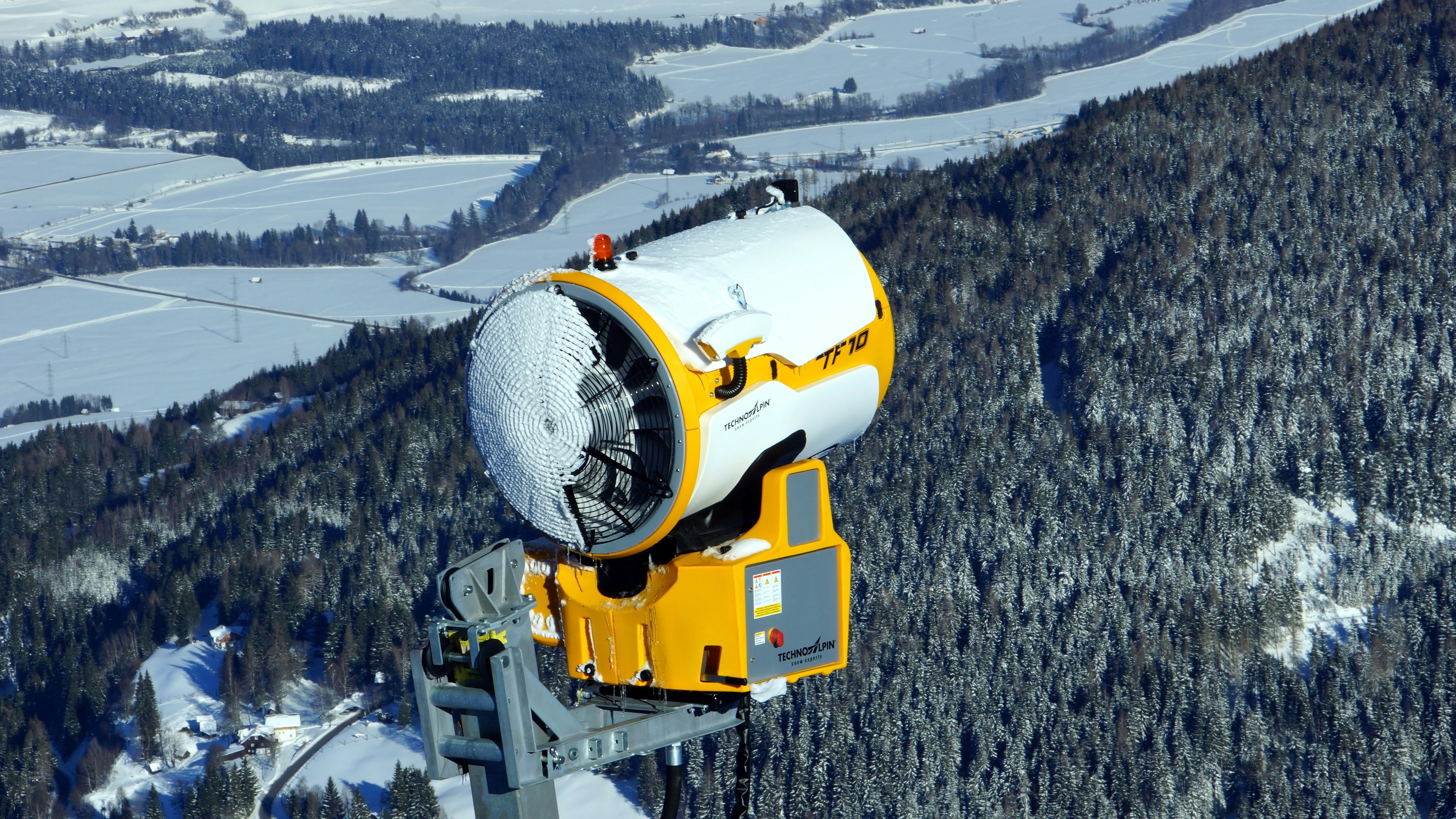 A yellow and white telescope sitting on top of a snow covered mountain ...
