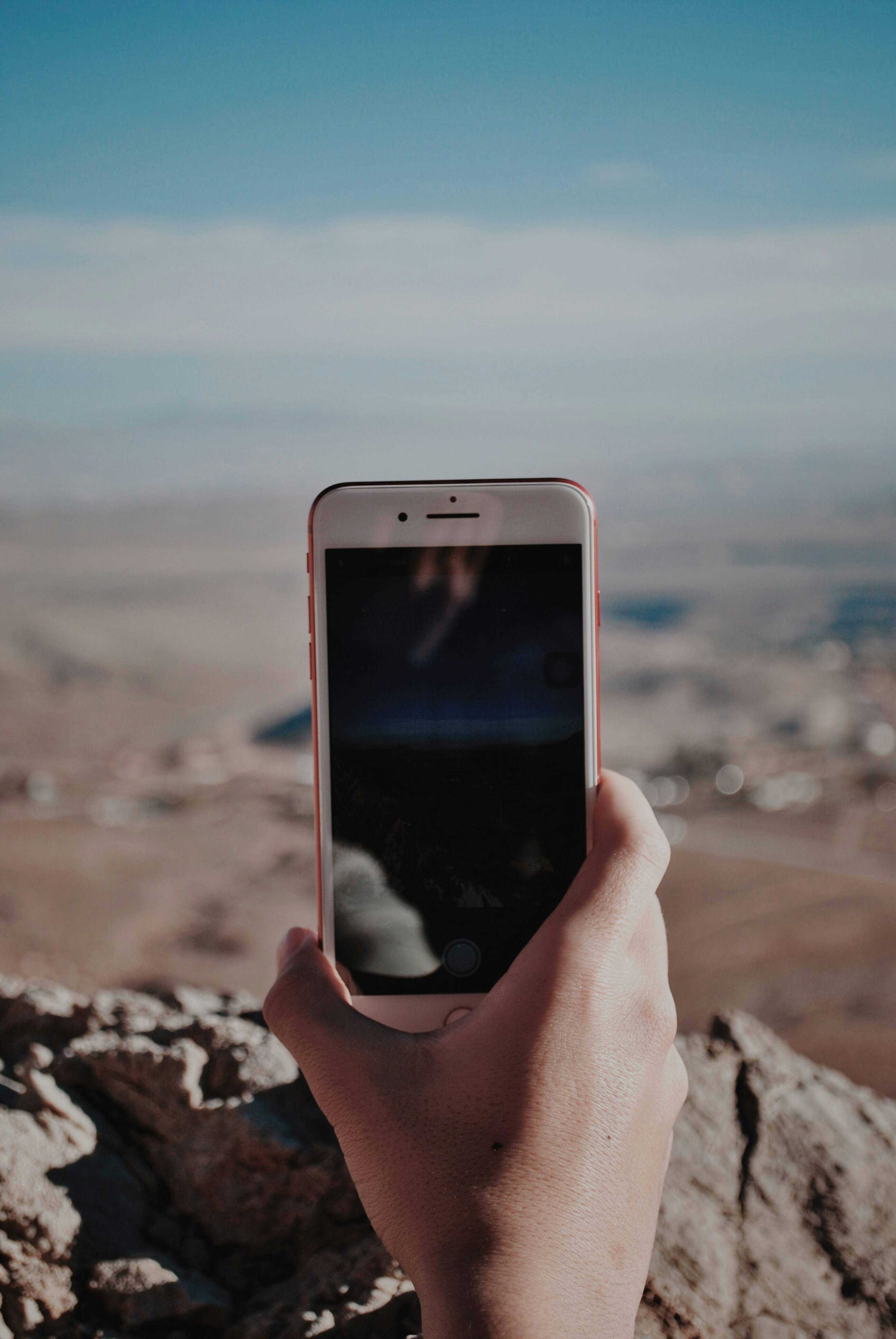 A Hand-Held Phone Framing a Quiet Desert Horizon
