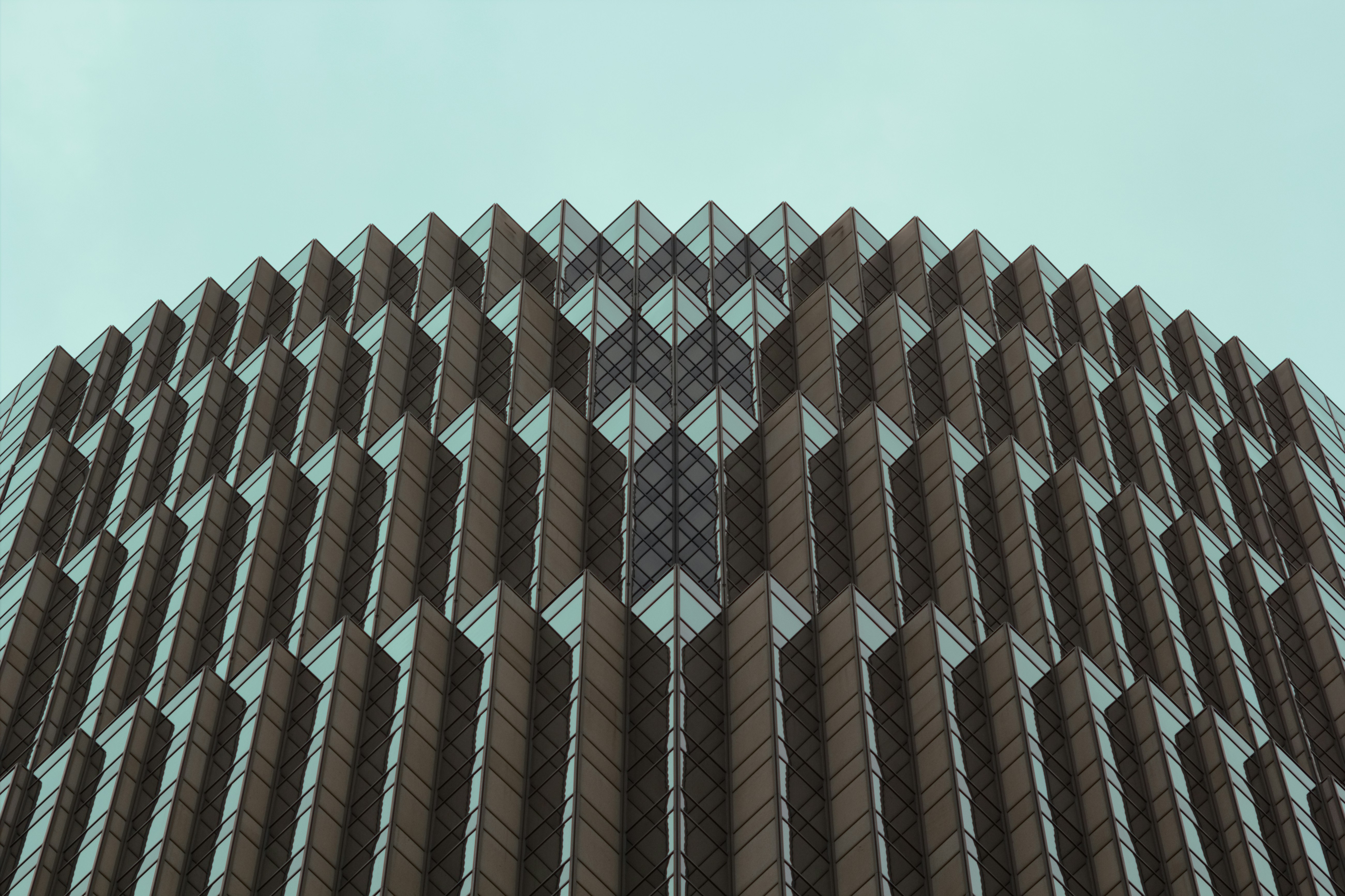 Abstract architectural facade showcasing a series of angular glass and metal panels. The design emphasizes symmetry and modern aesthetics.