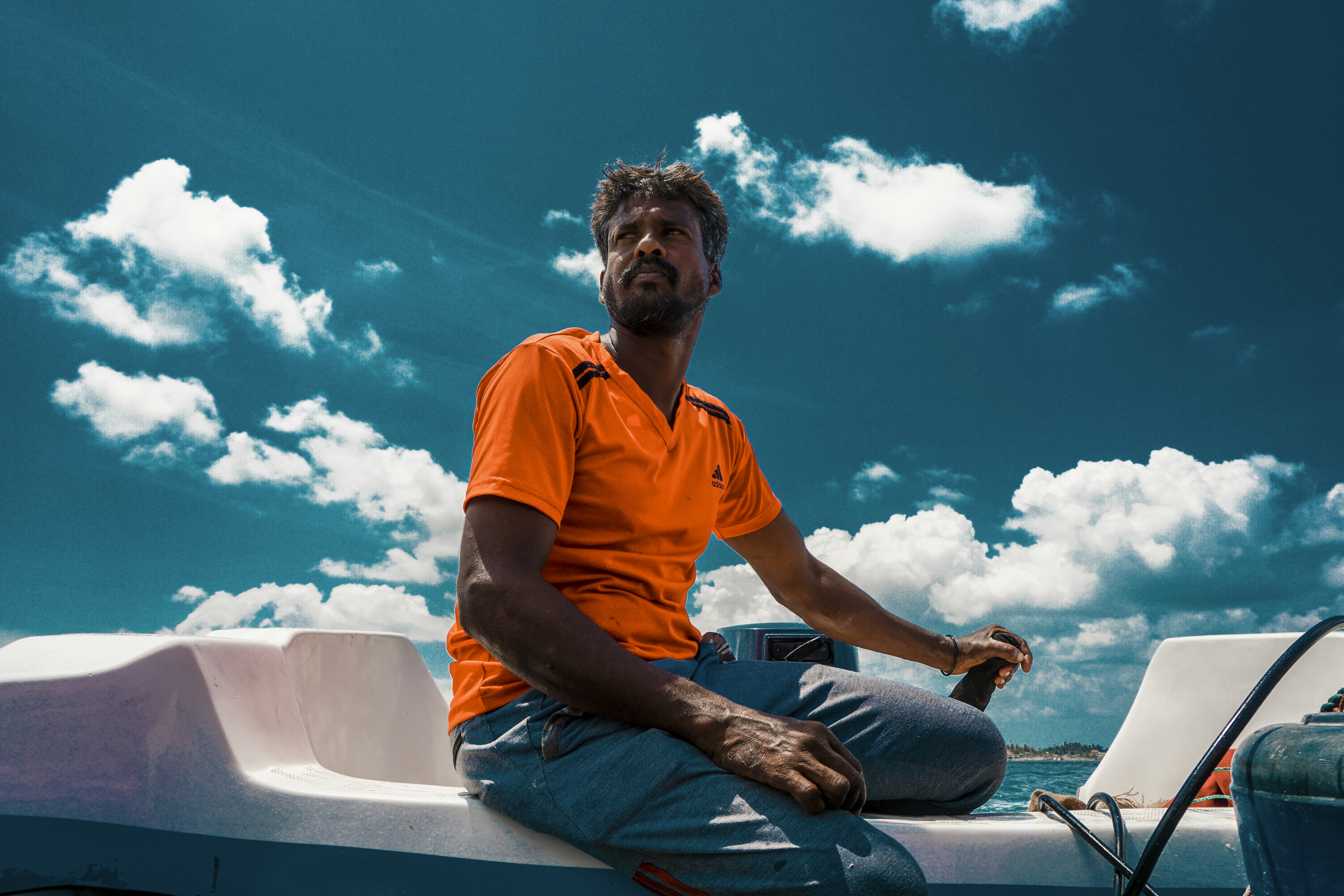 Orange Shirt, Blue Sky: A man rides shotgun on a sunlit boat