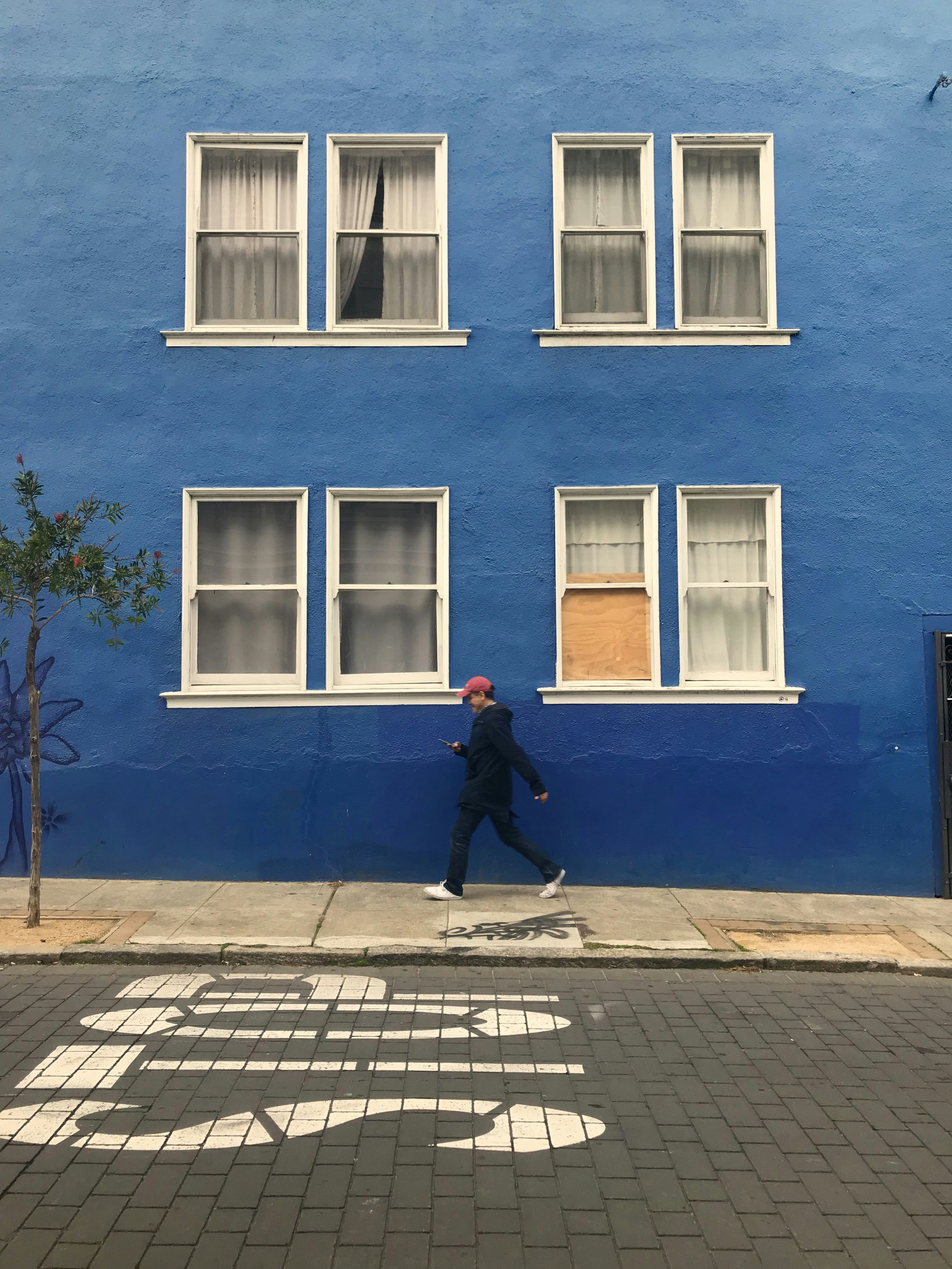 Cobalt Facade, Quiet Stride: A Moment Along the Blue Street