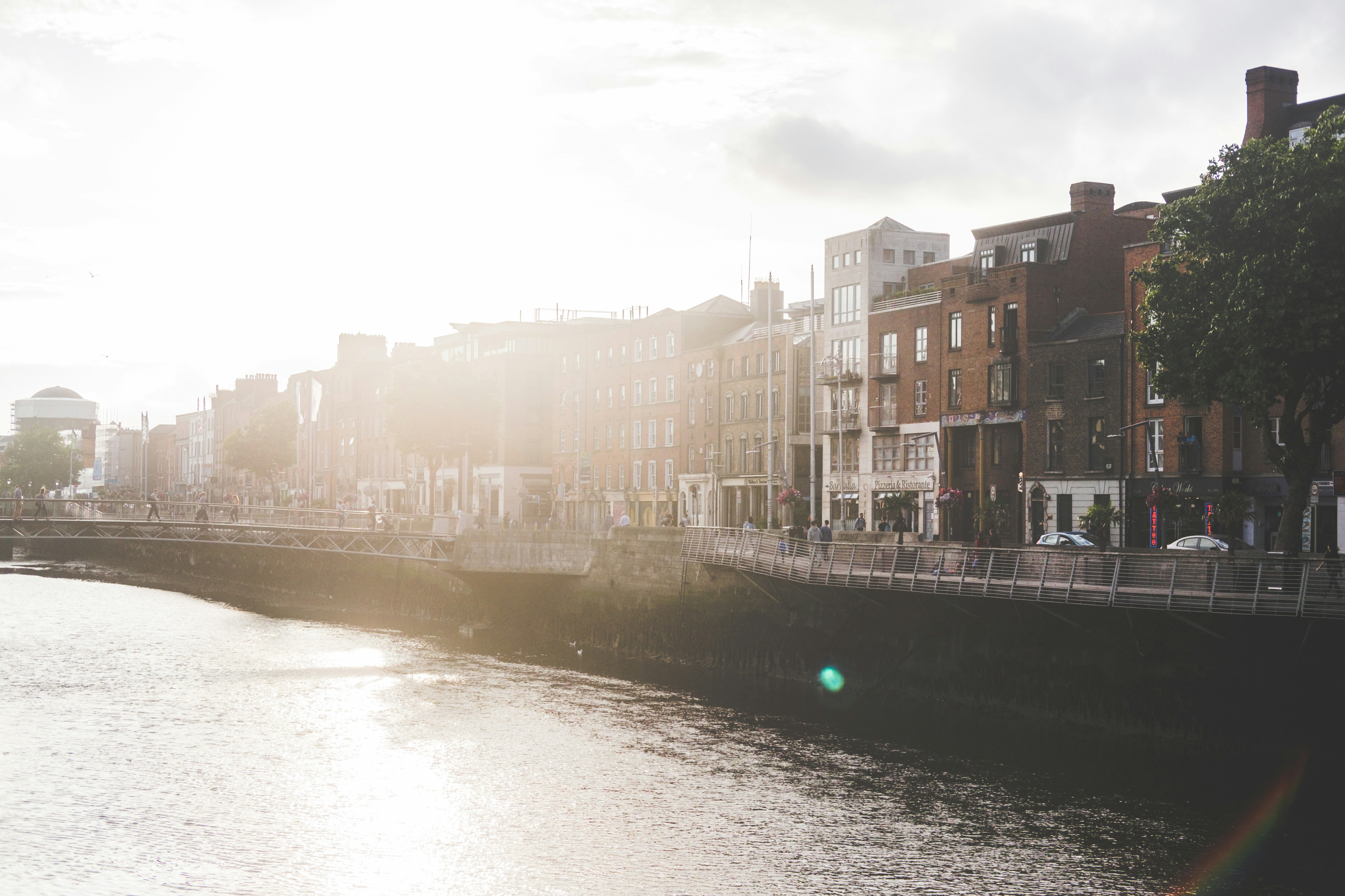 Riverside buildings bathed in warm sunlight under a cloudy sky.