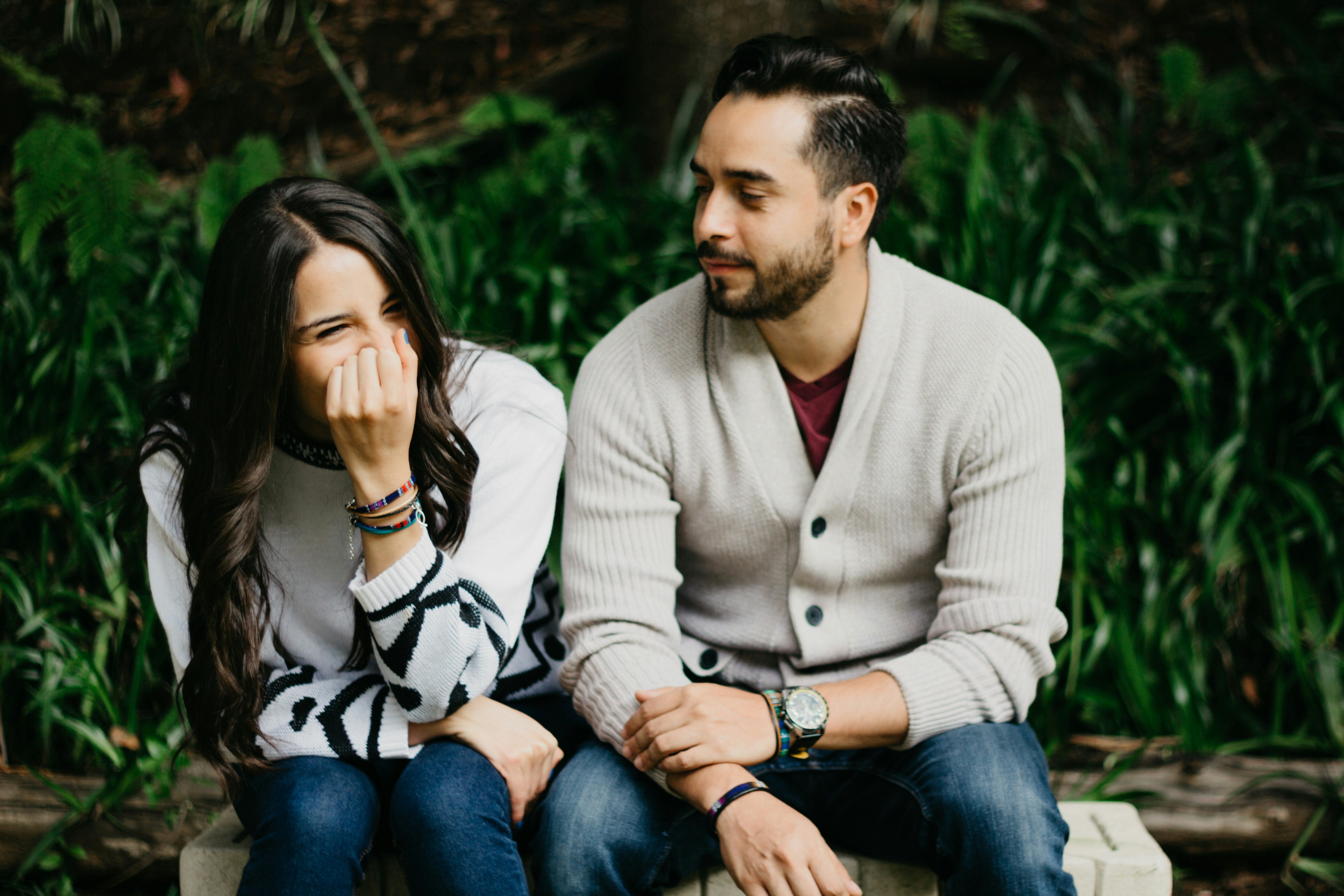 Two friends share a moment of laughter amidst lush greenery, capturing the essence of joy and connection. The scene radiates warmth and camaraderie.