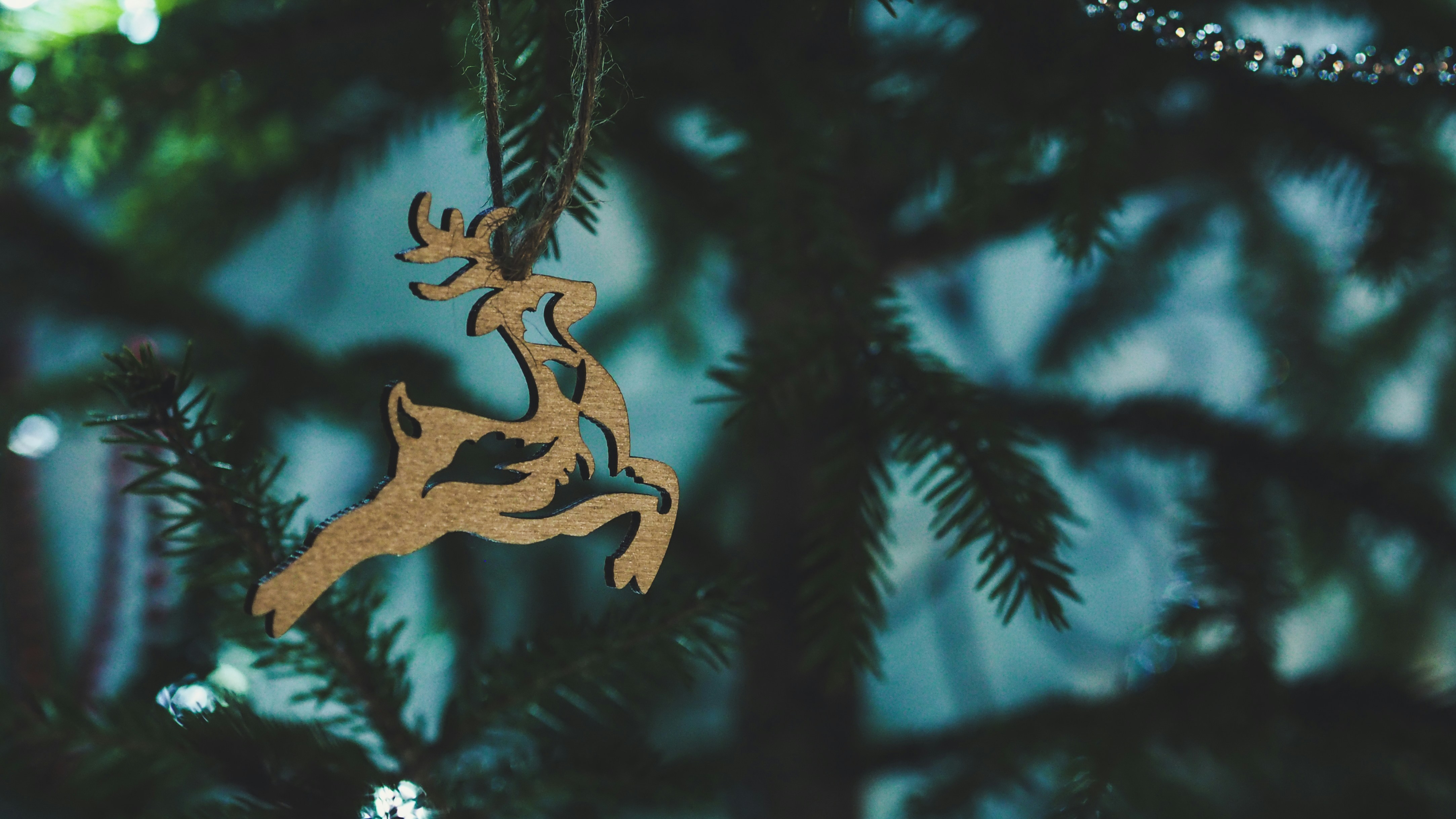 Golden reindeer ornament against a teal spruce backdrop