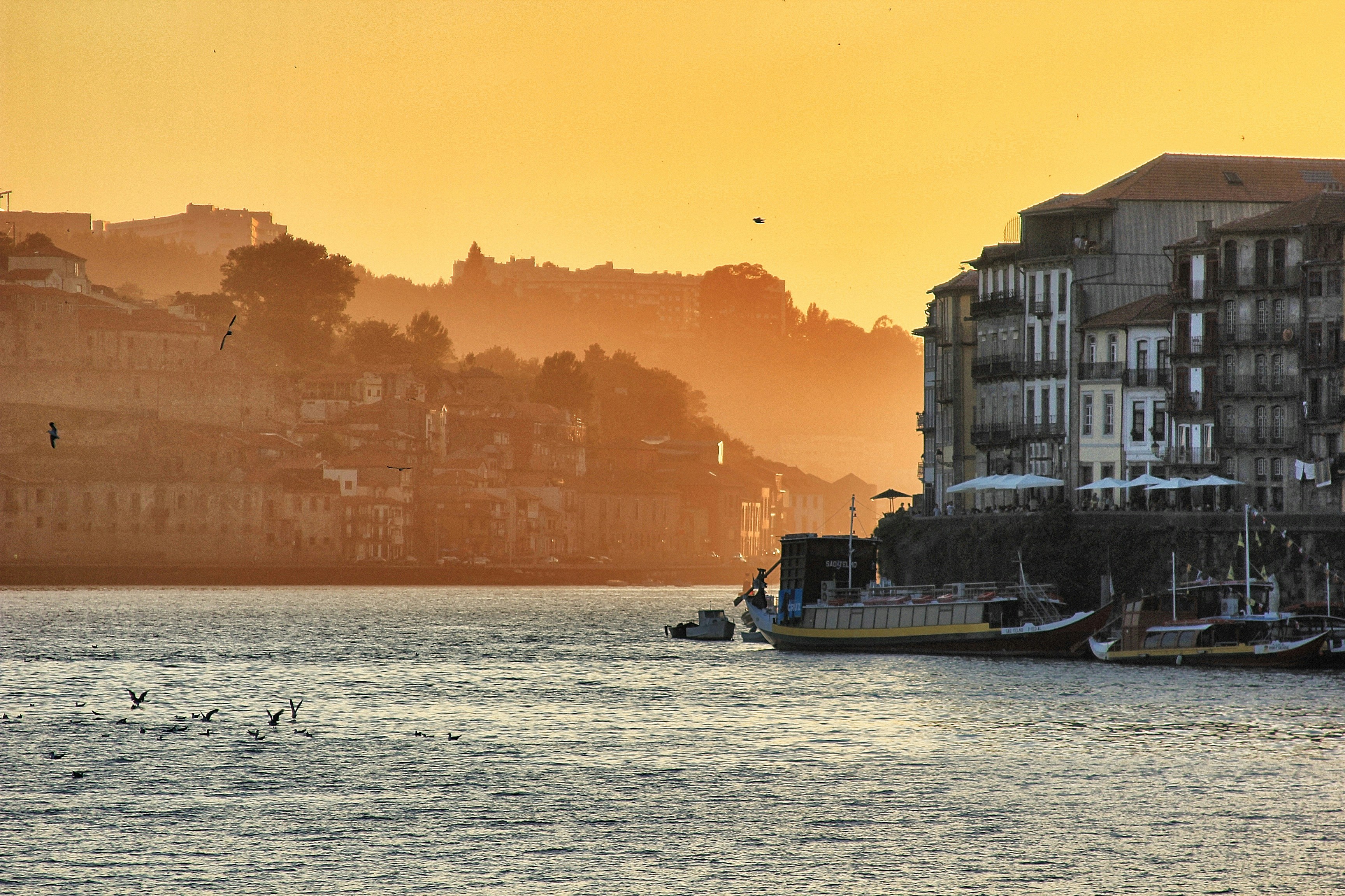 Sunset over the Douro River with silhouetted buildings and soft golden light.