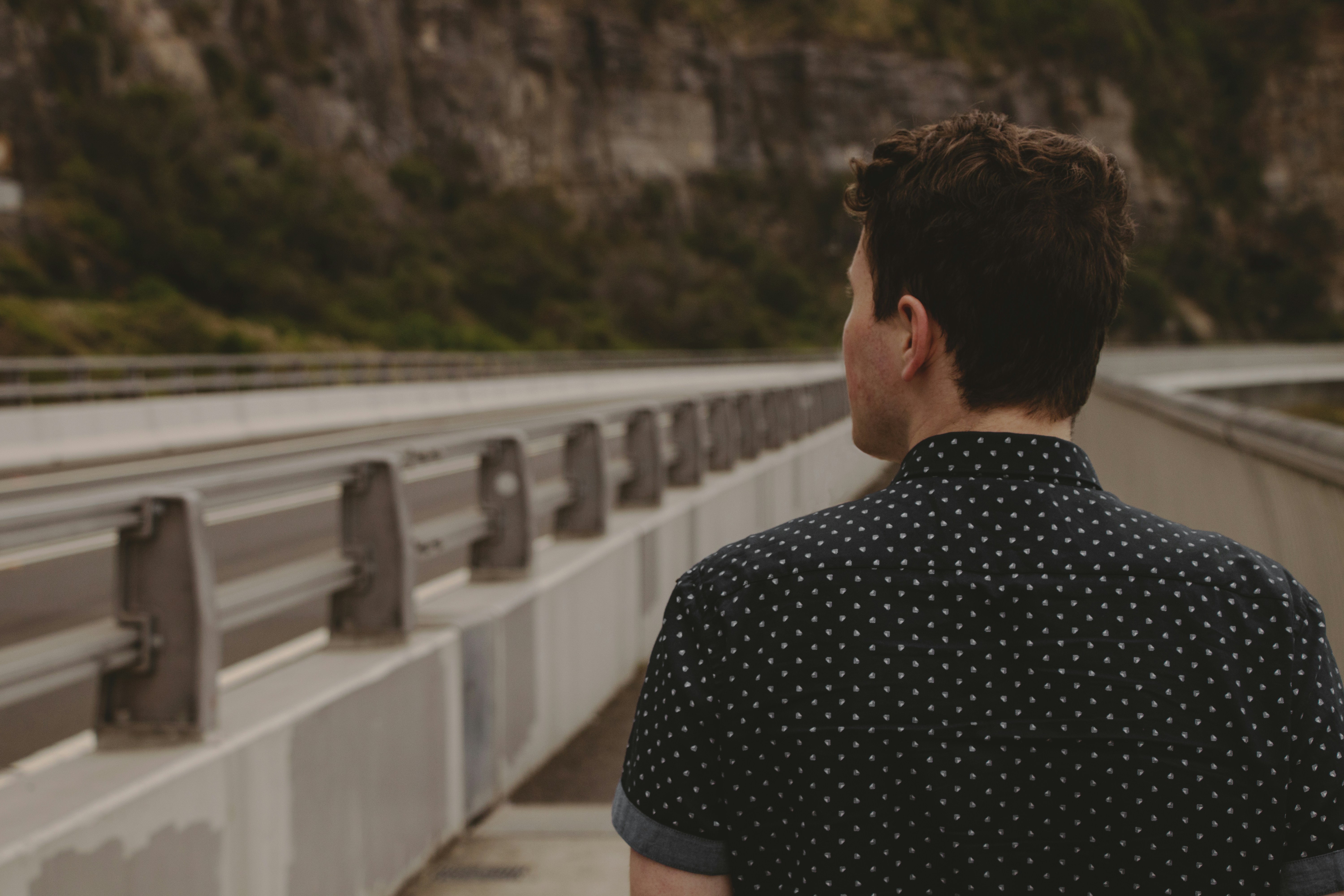 Man facing backward while walking along concrete bridge photo – Free ...