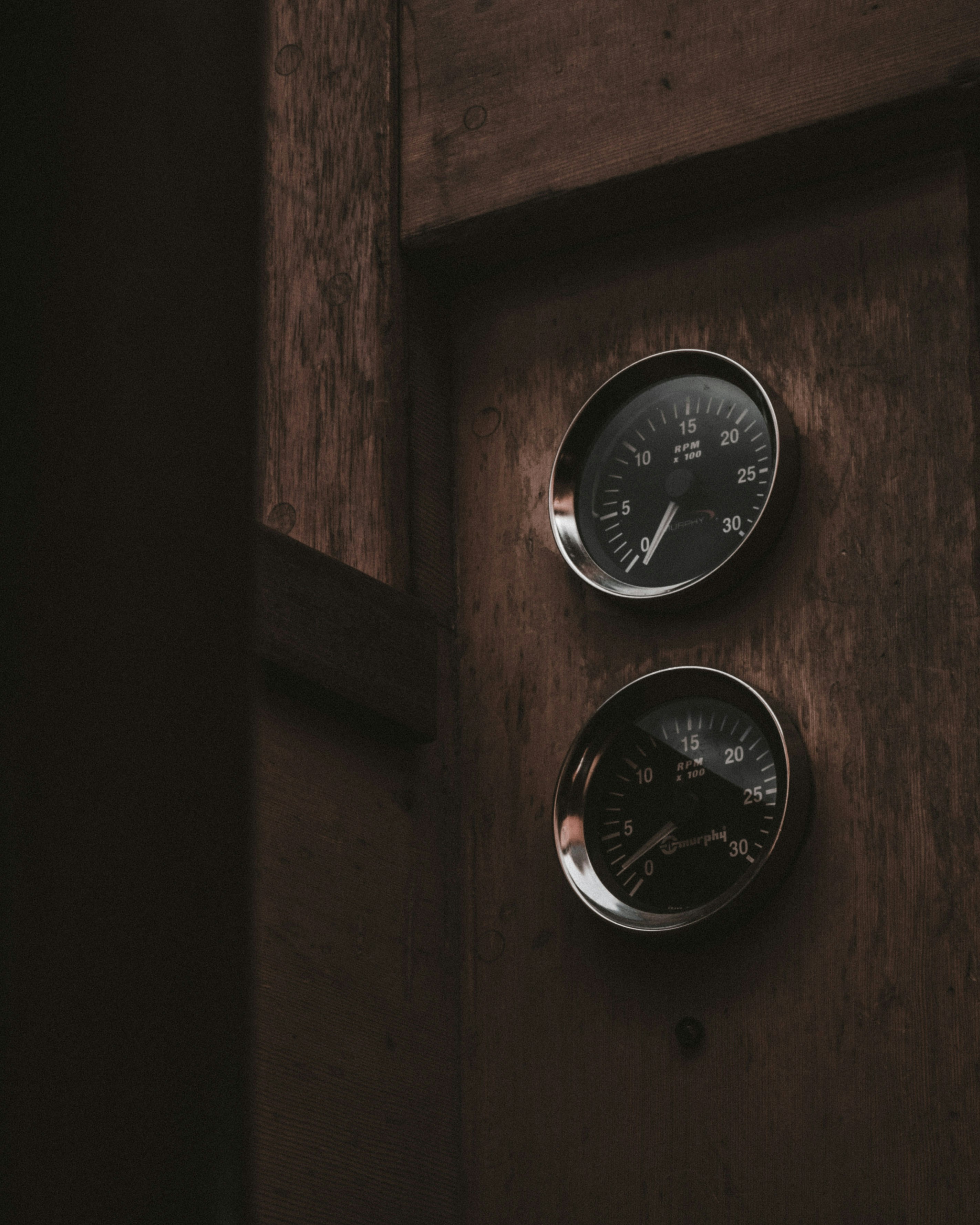 Two vintage gauges mounted on a wooden wall, showcasing their intricate dials and detailed markings.
