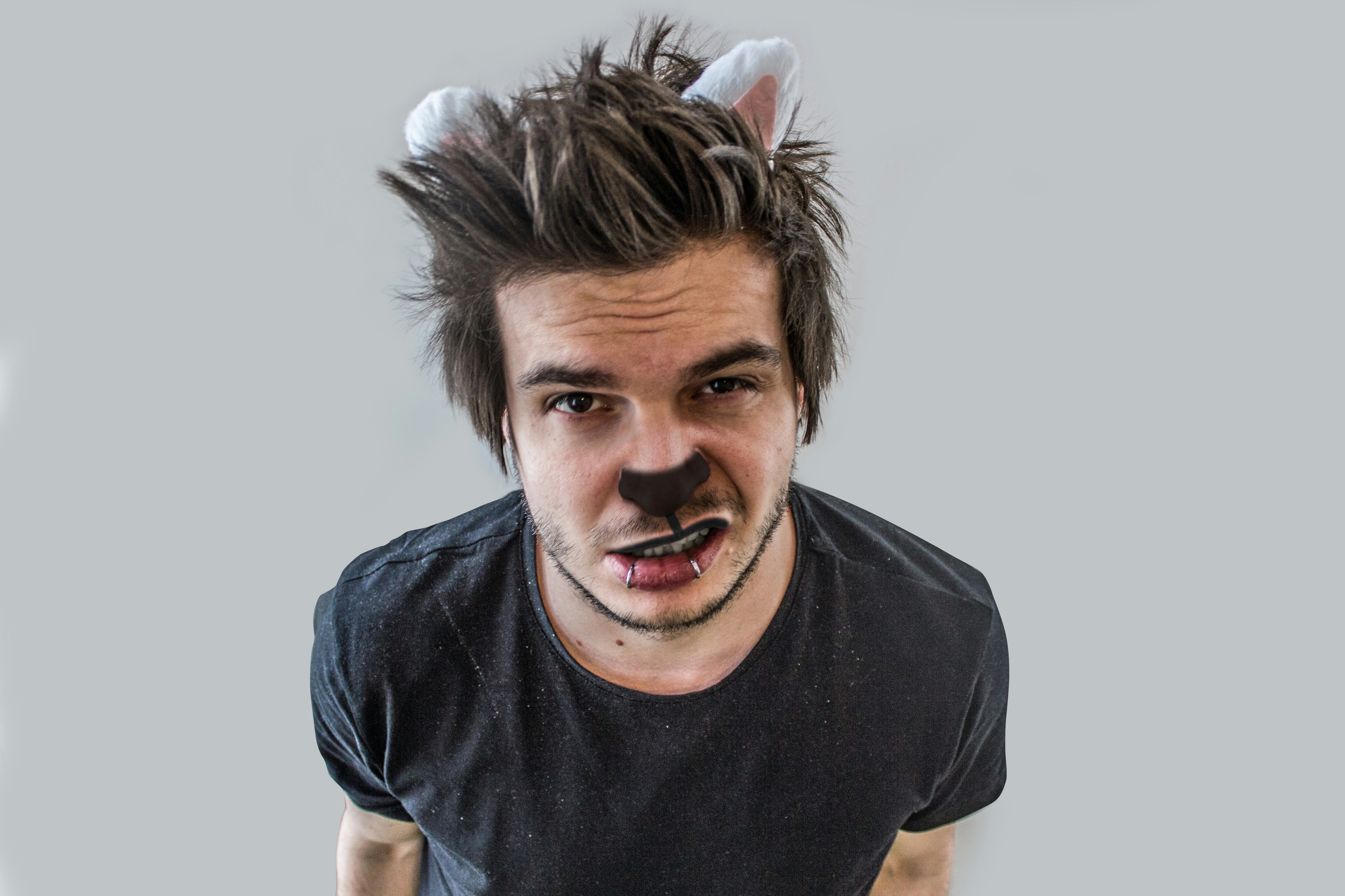 Young man with playful animal features, including ears and a nose, poses against a neutral background, exuding a fun and quirky vibe.