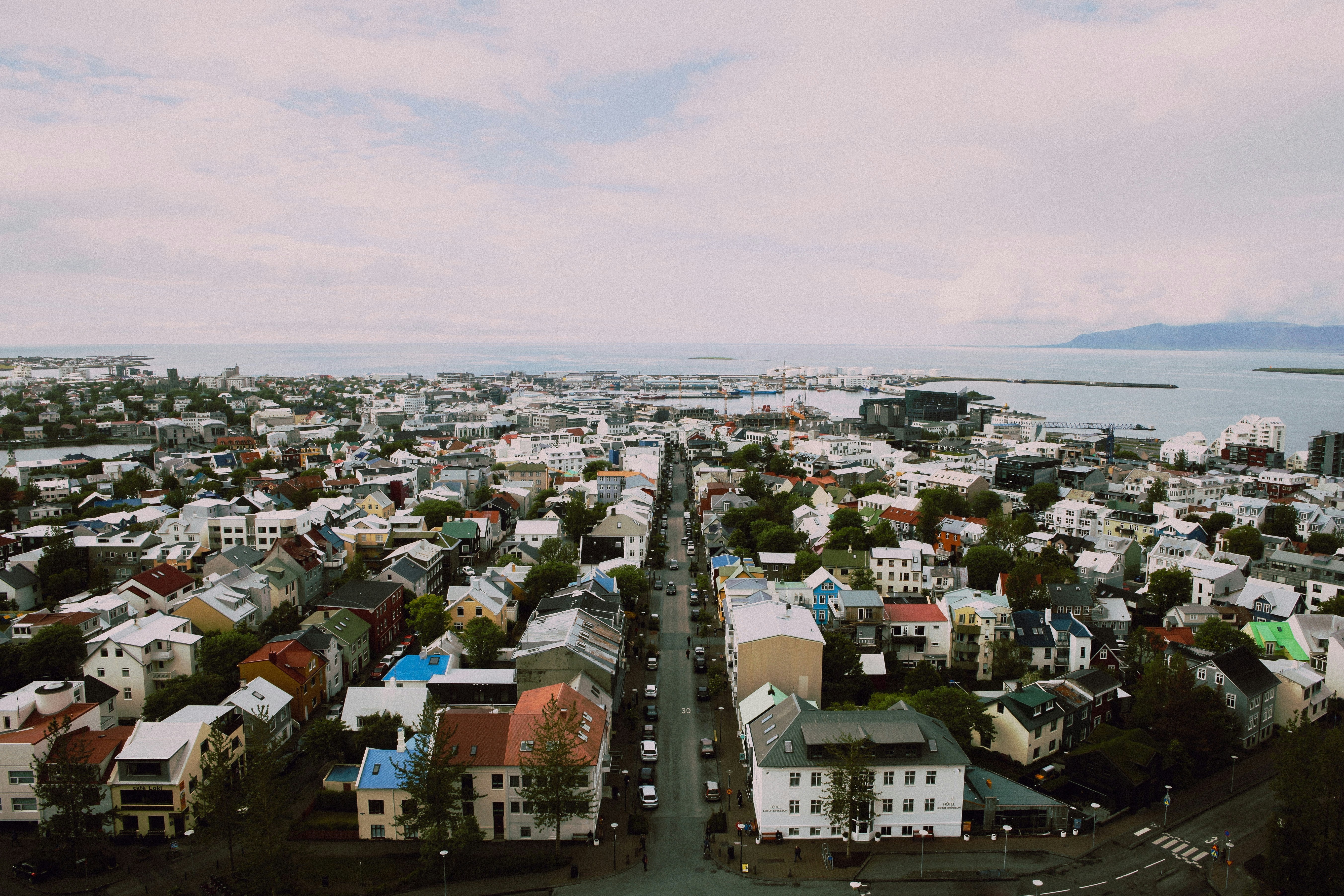 Aerial view of a coastal cityscape with colorful buildings and a central road leading towards the sea.