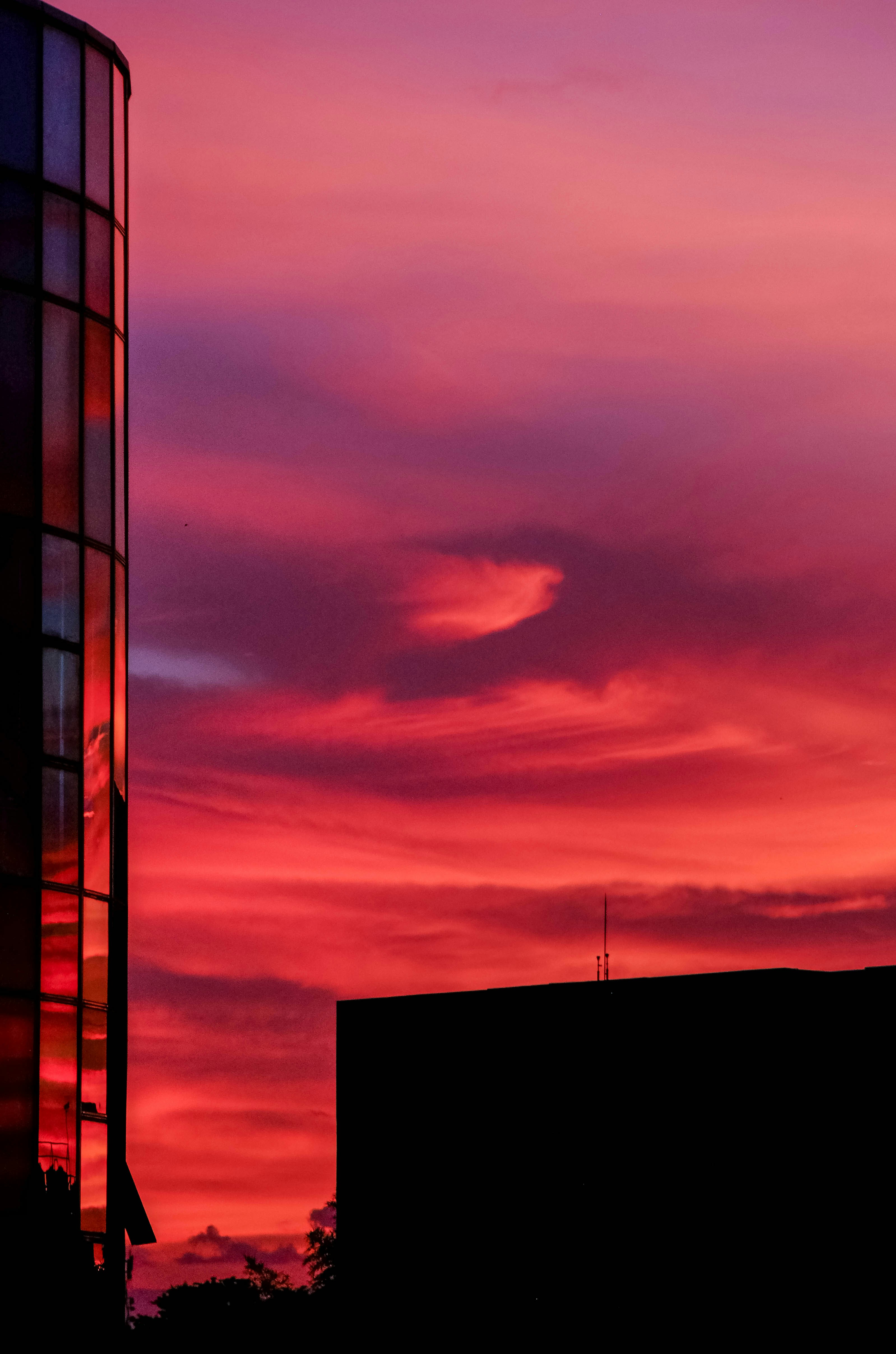 Vibrant pink and orange sunset behind modern building silhouettes.