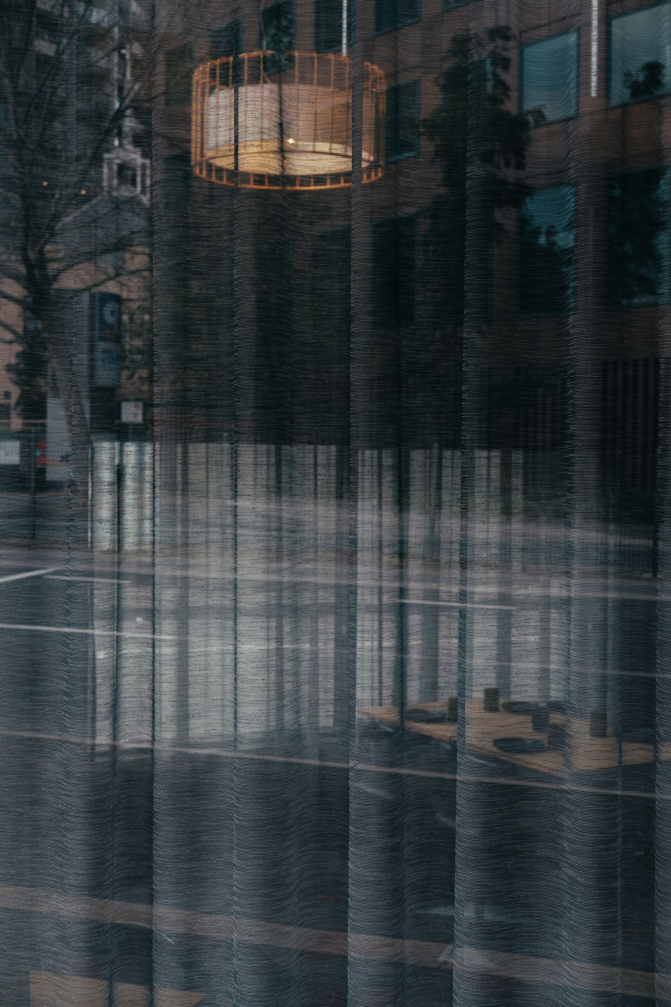 Softly draped curtain reflecting the urban landscape, with a warm light fixture overhead creating a cozy ambiance.
