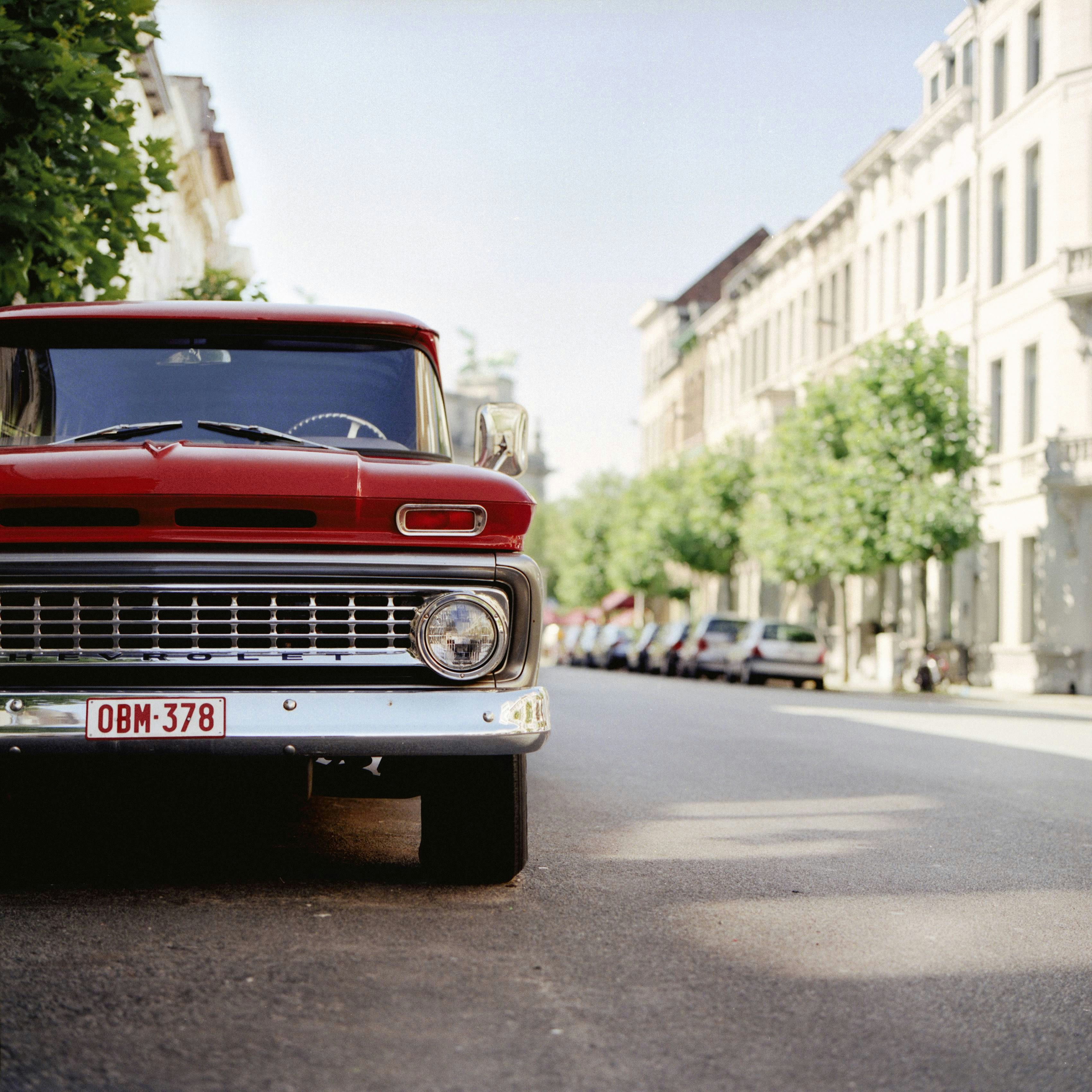Red Vintage Pickup on a Sunlit City Street — Chrome Grille in Focus