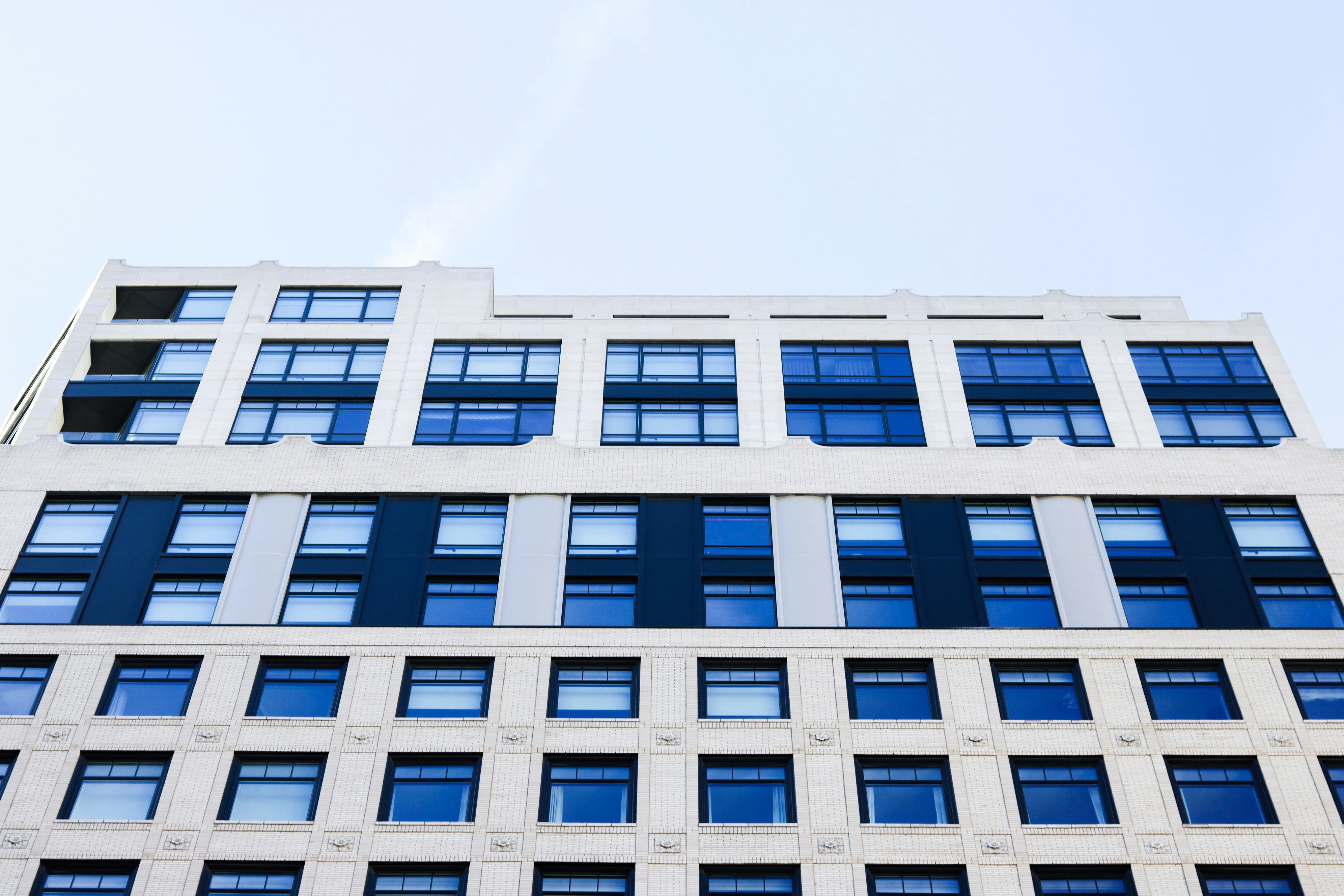 Contemporary building facade showcasing a rhythmic arrangement of windows in contrasting colors against a clear sky.