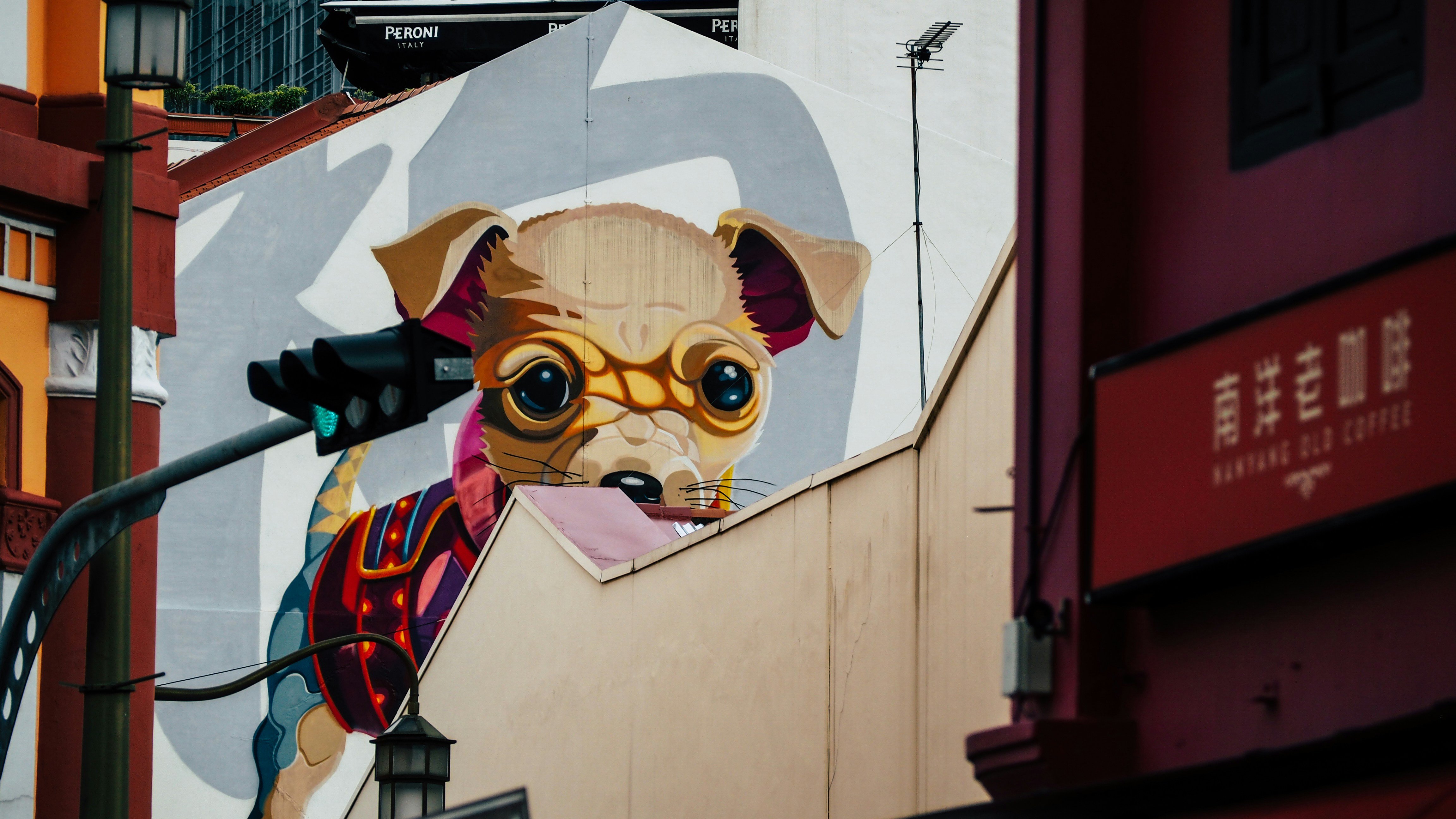Vibrant mural of a playful dog peeking over a wall in an urban setting, showcasing colorful artistry and street culture.
