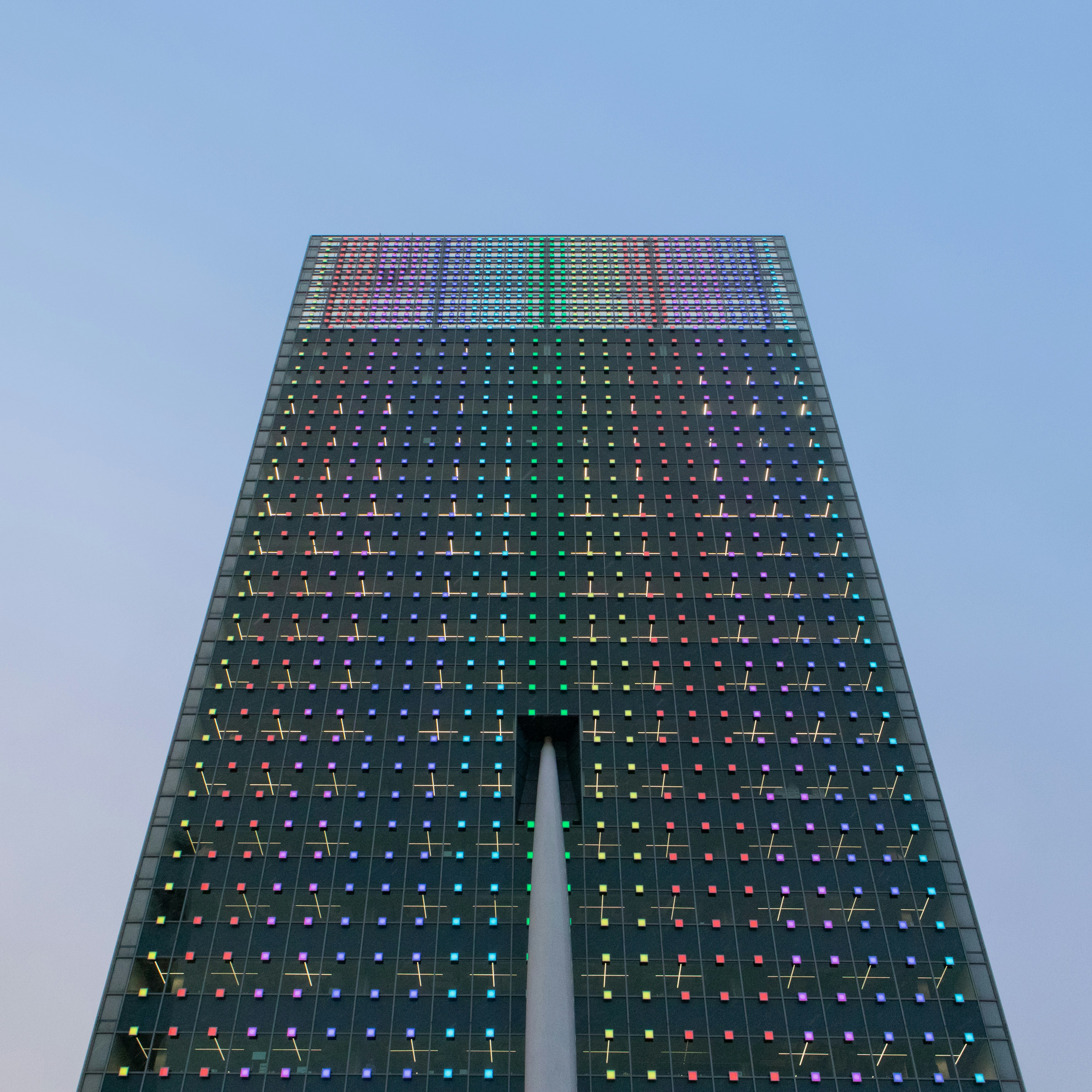 Illuminated skyscraper facade showcasing a vibrant pattern of lights against a twilight sky.