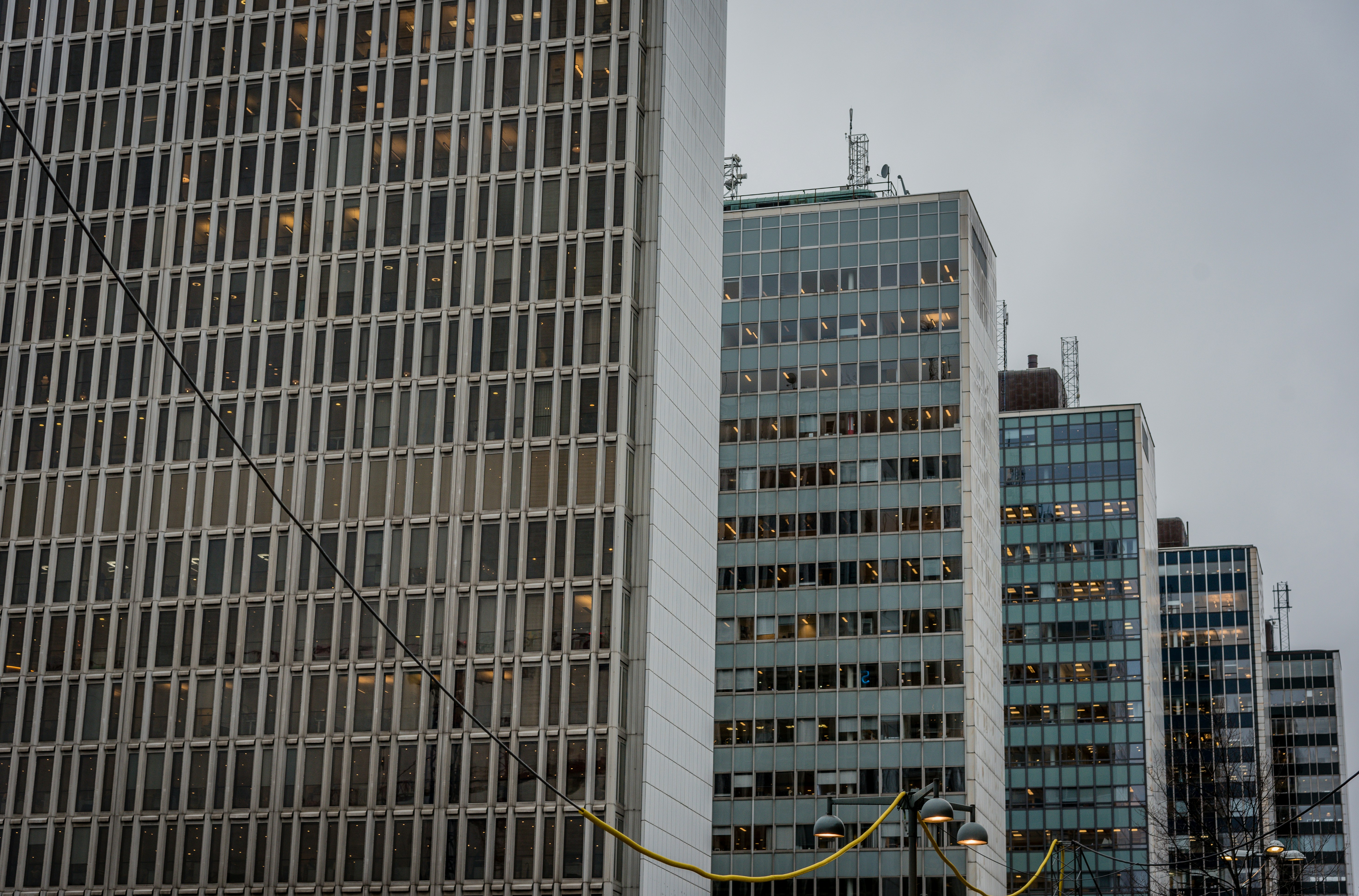 Modern skyscrapers with a mix of reflective glass and concrete facades, showcasing urban architecture against a gray sky.