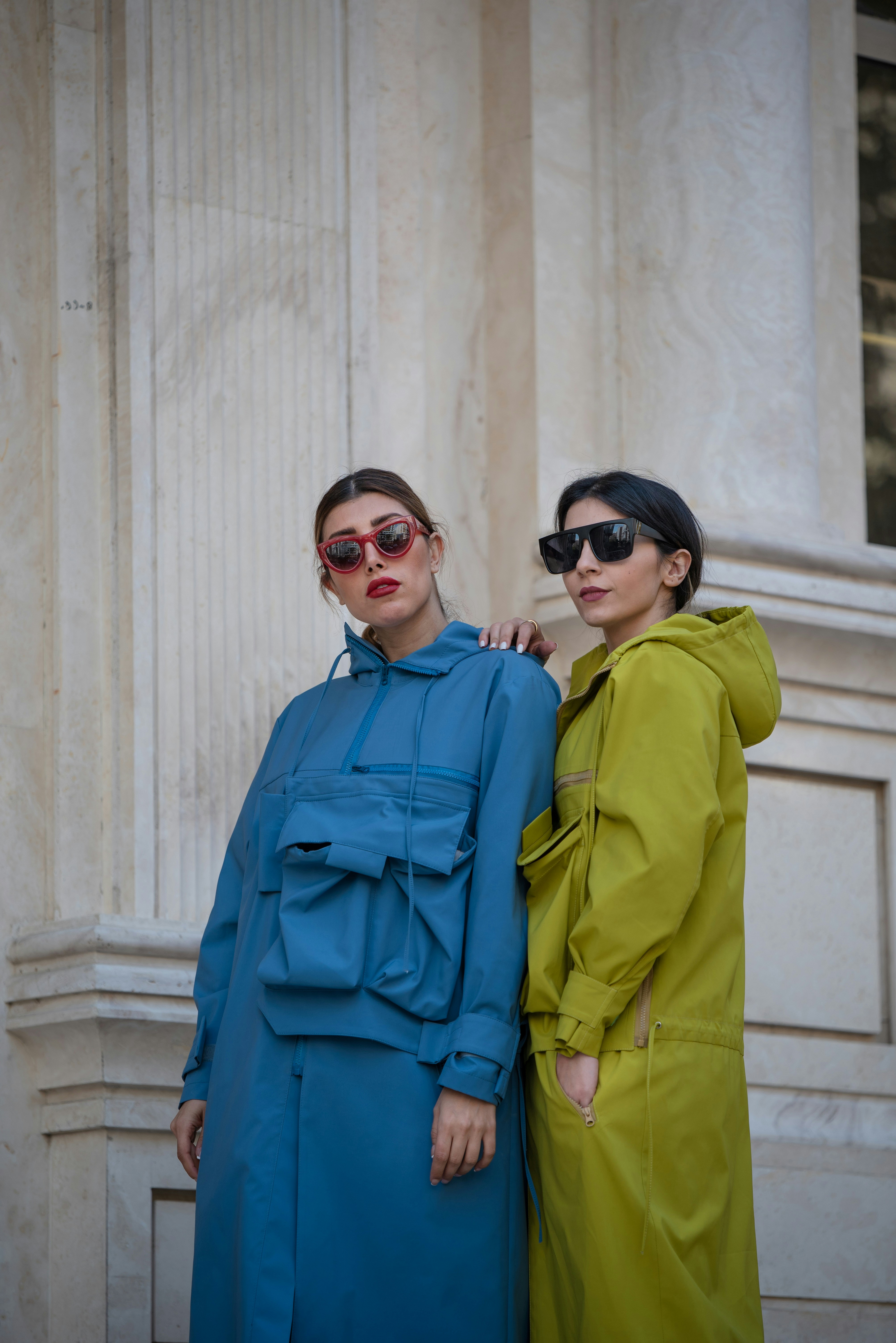 Two Color Narratives: Blue and Olive Cloaks Beside an Ancient Facade