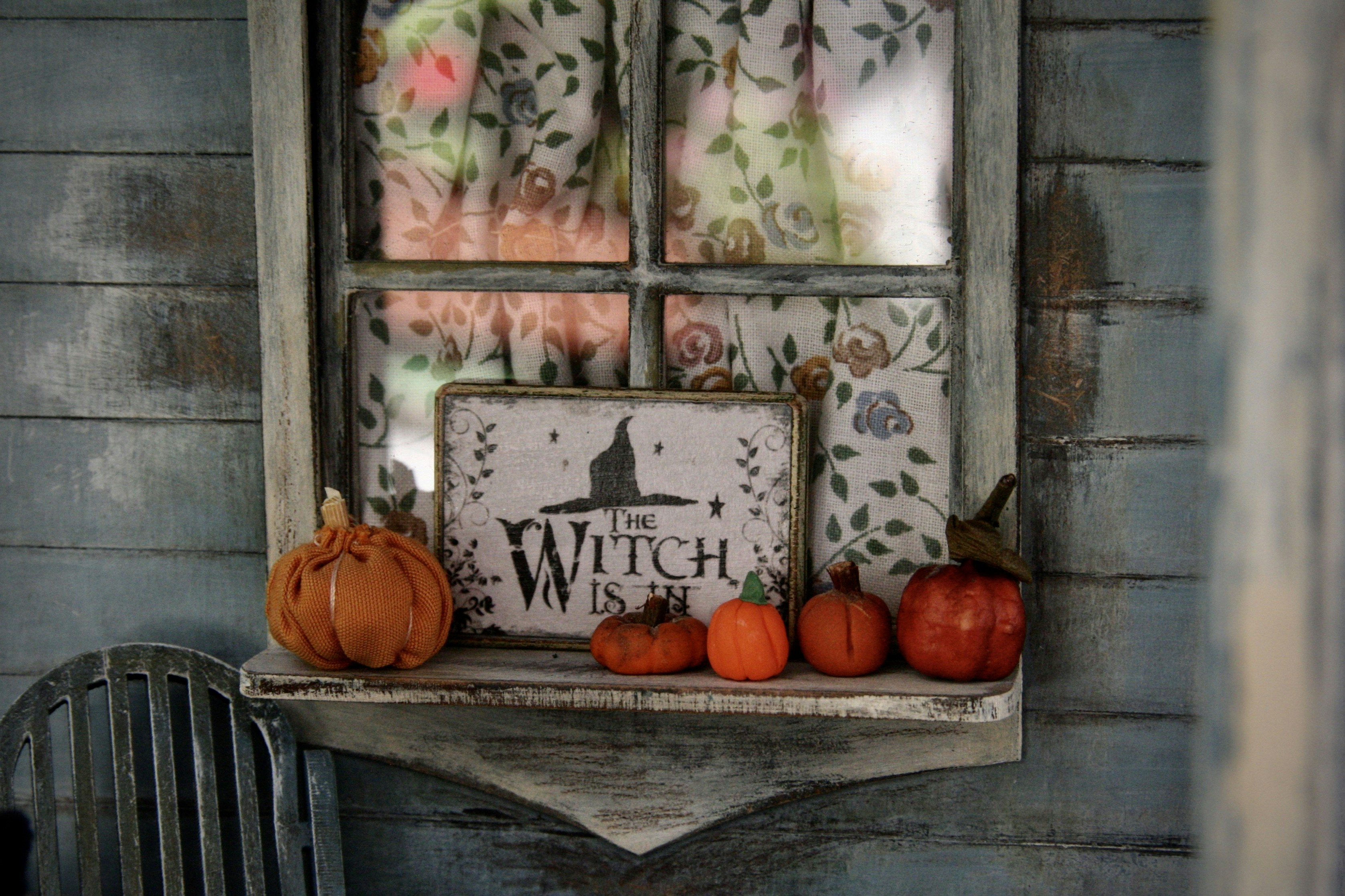 A rustic window adorned with a whimsical witch-themed sign and an array of pumpkins, capturing the essence of fall decor.