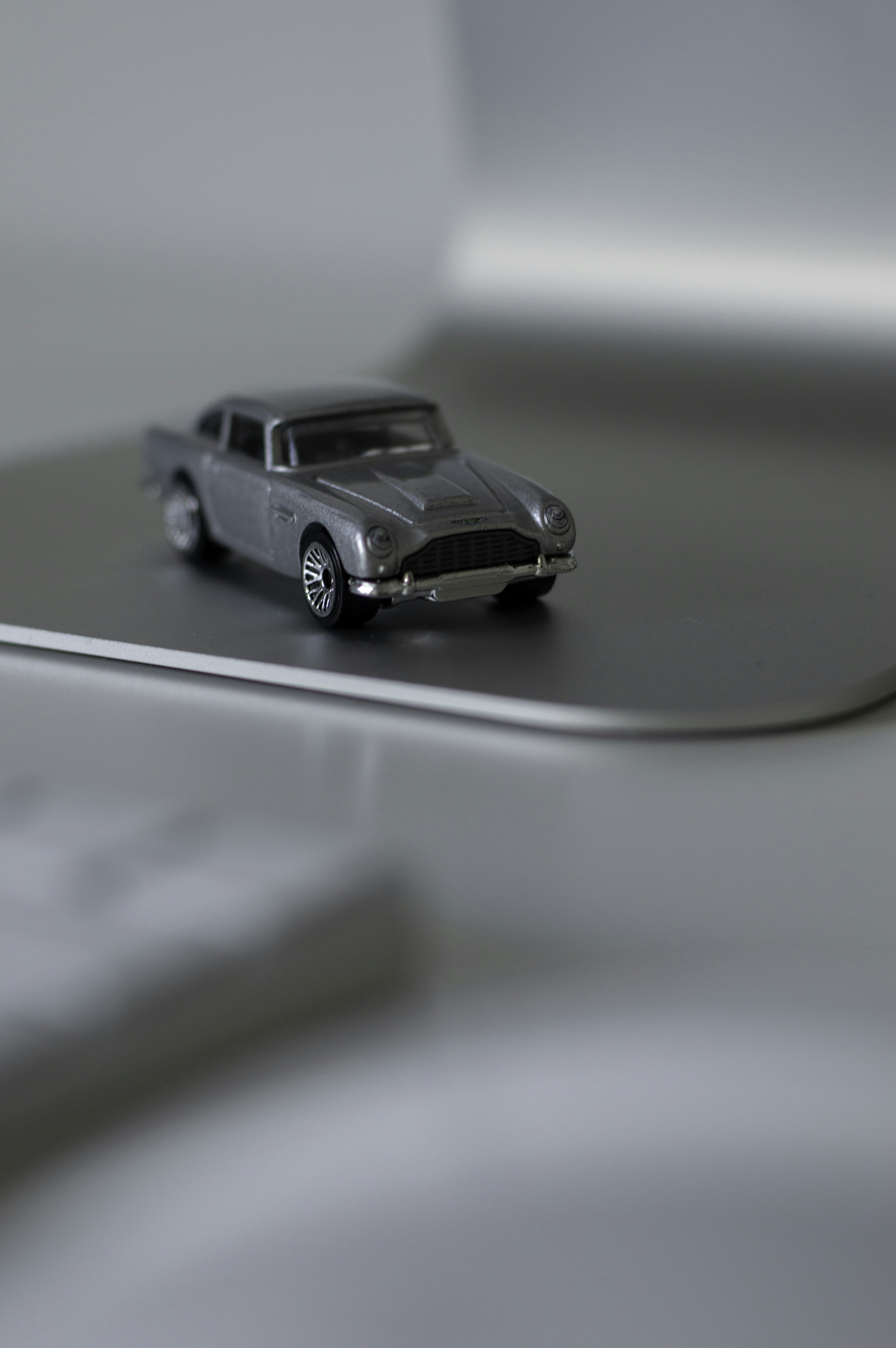 A detailed silver miniature car resting on a sleek surface, highlighting its vintage design and craftsmanship.