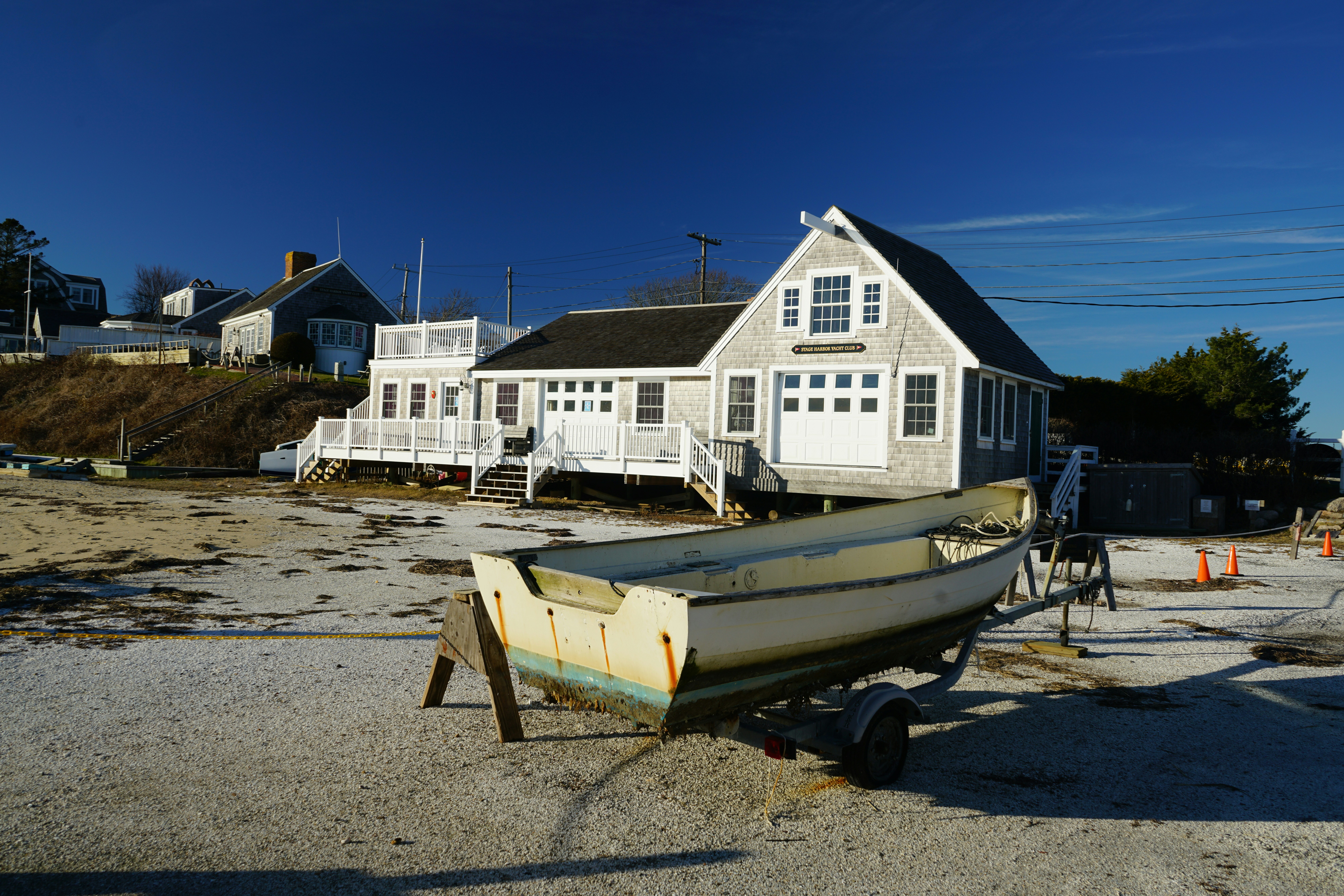 Weathered Boat on a Gravel Stage Before a Row of Seaside Cottages