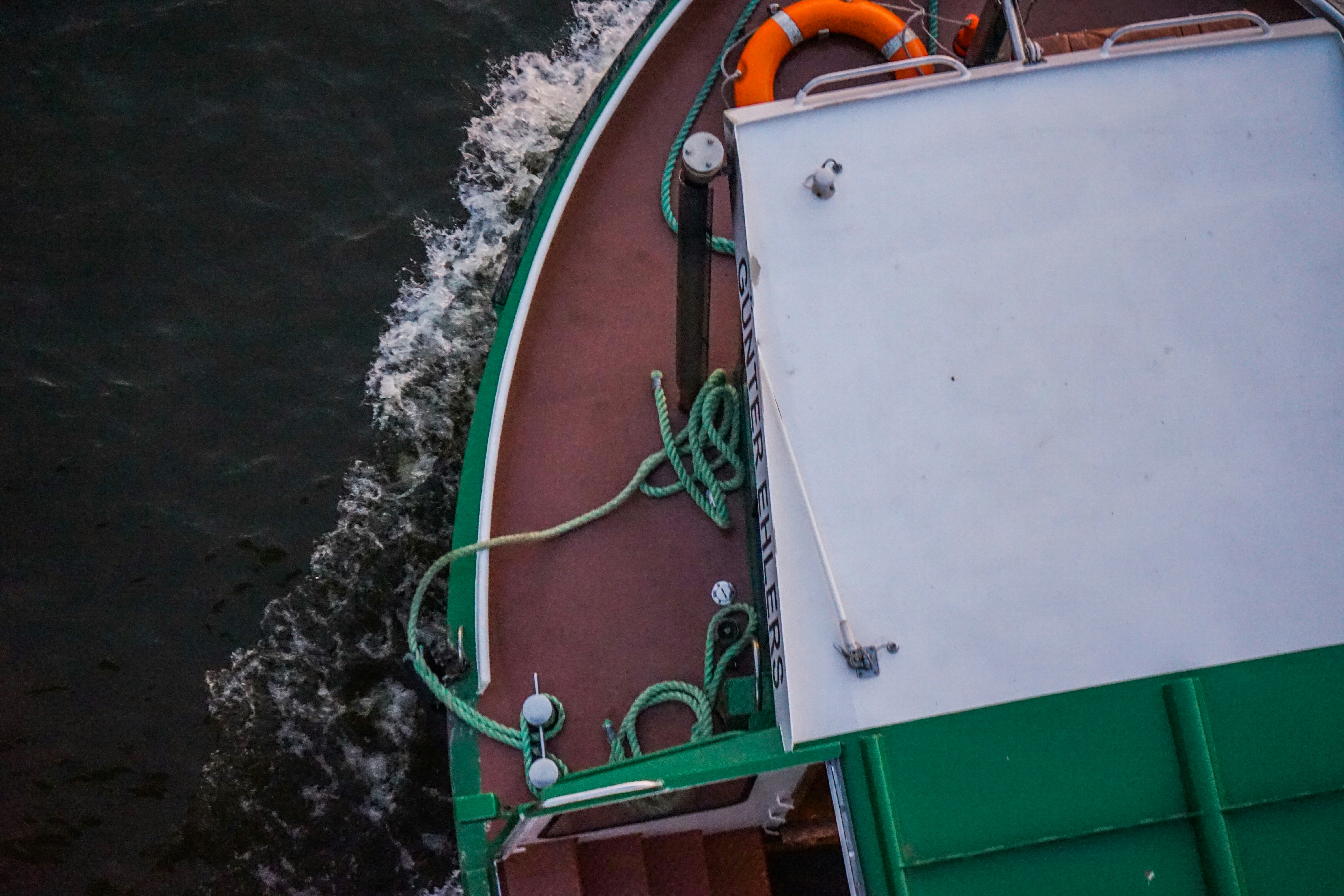 Top-Down Portrait of a Workboat Deck: Green Hull, Orange Lifebuoy, and Tidy Ropes