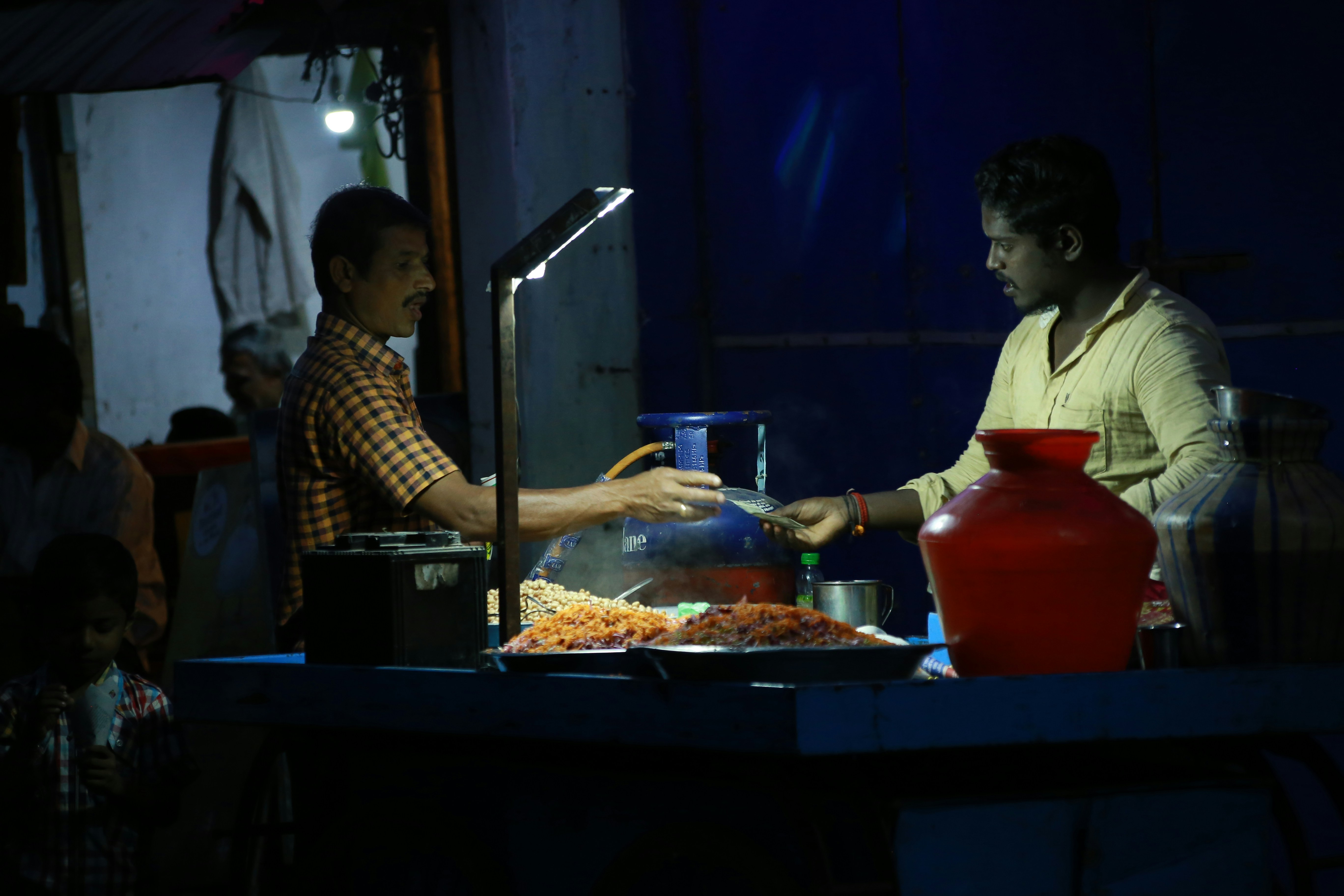 Cobalt Glow and Handshake at a Night Market Stall