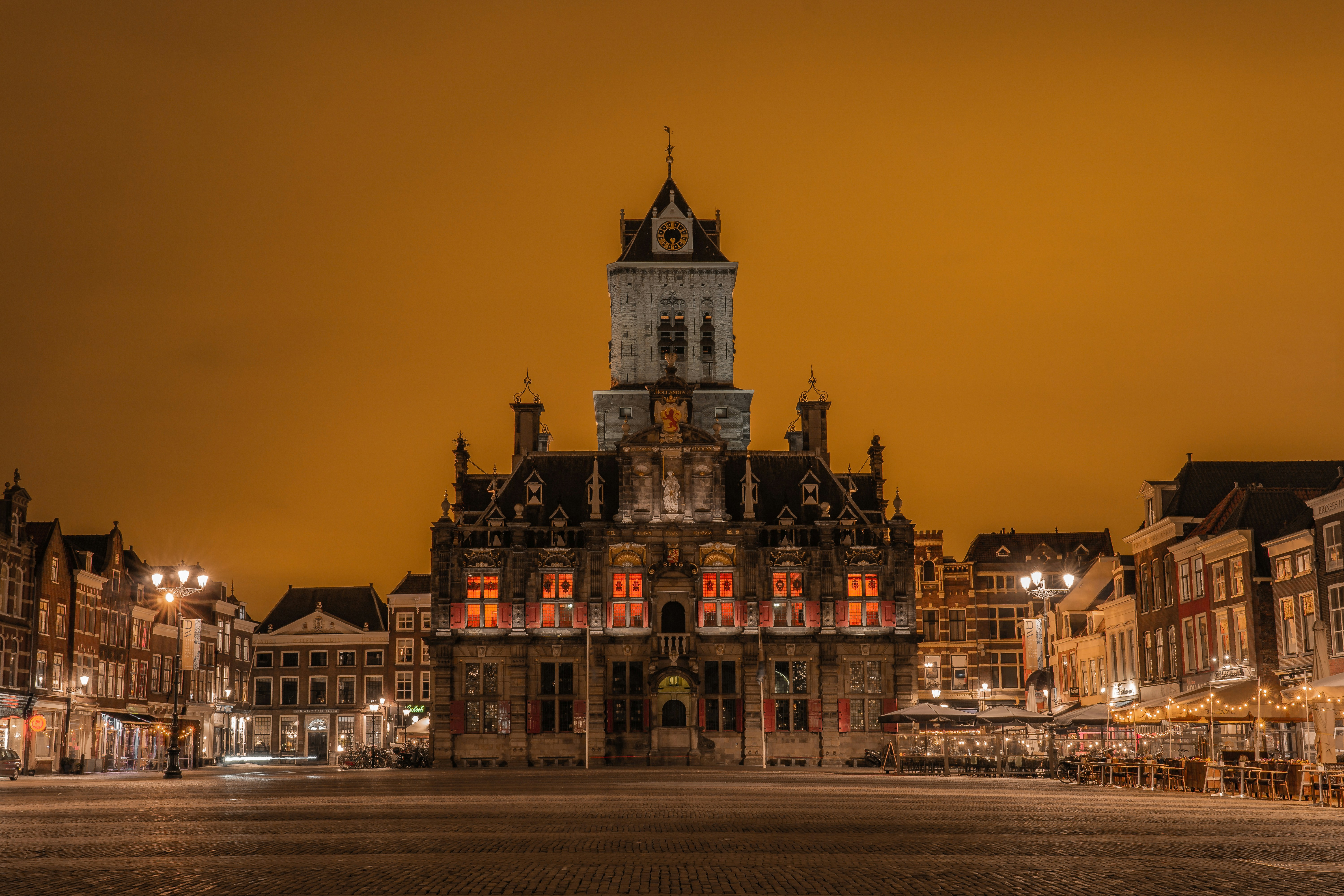 Historic building with ornate façade lit in orange hues under a glowing amber sky.