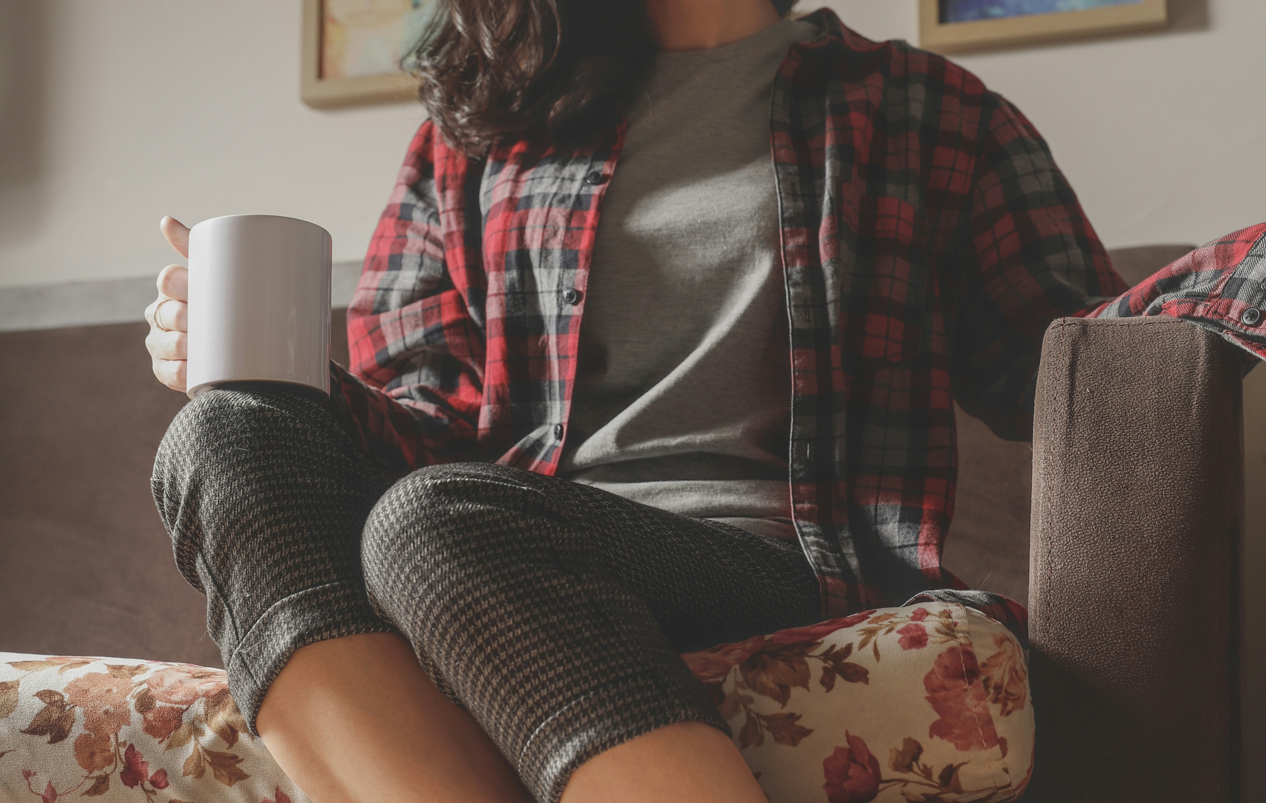 Mug-Warmed Quiet: Plaid Comfort on a Floral Sofa