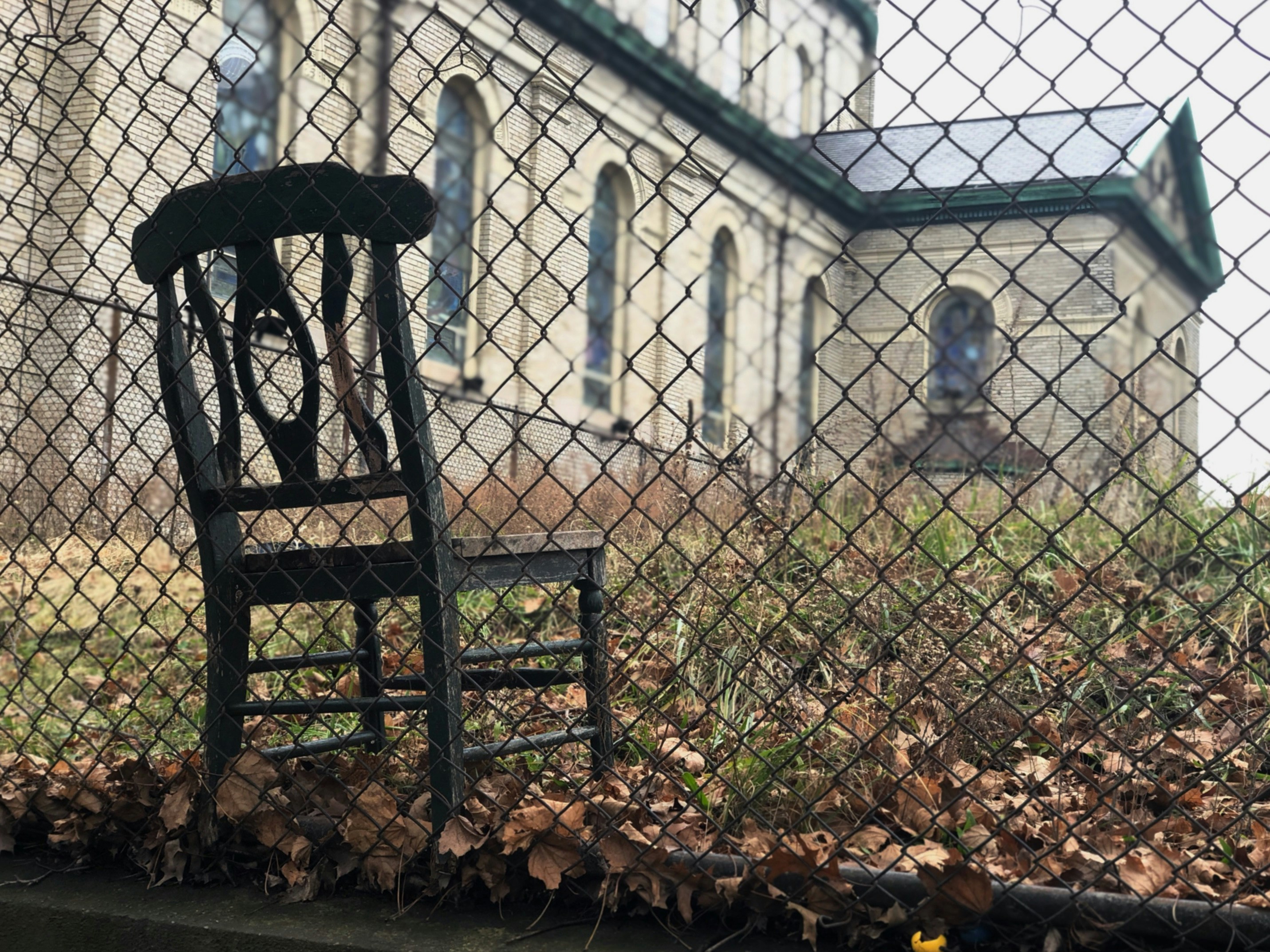 The Fence's Frame: A Quiet Chair by an Old Church