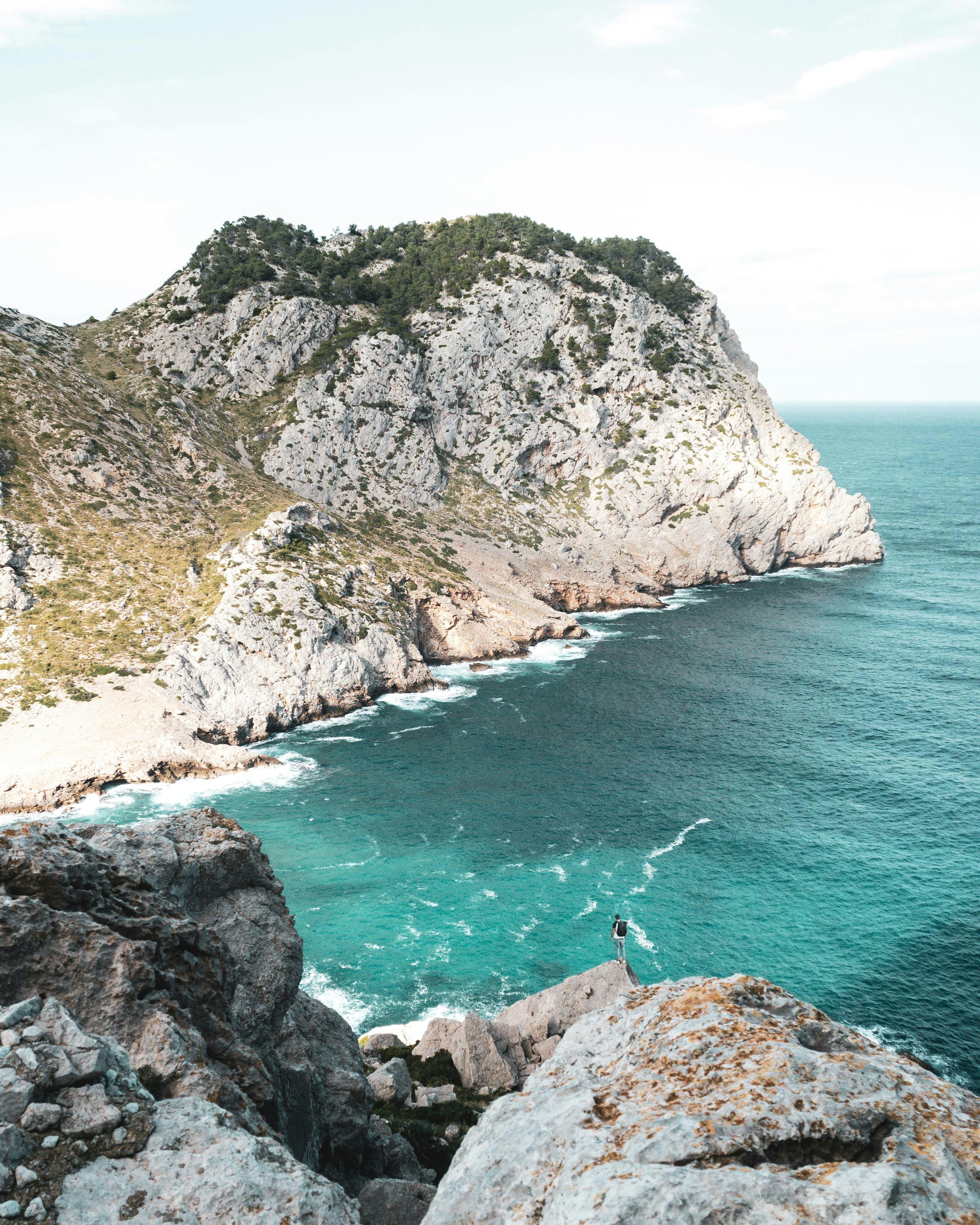 Rocky cliffs meet the turquoise sea under a bright sky.