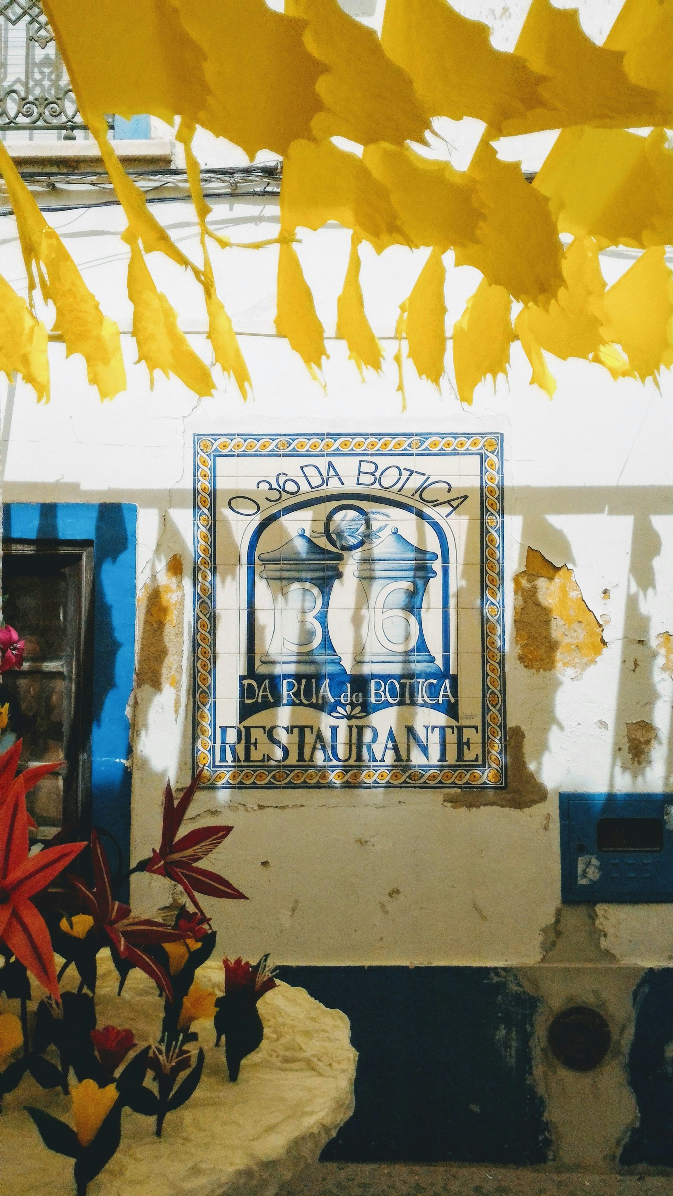 Colorful restaurant sign adorned with decorative flowers against a rustic wall, showcasing local culture and cuisine.