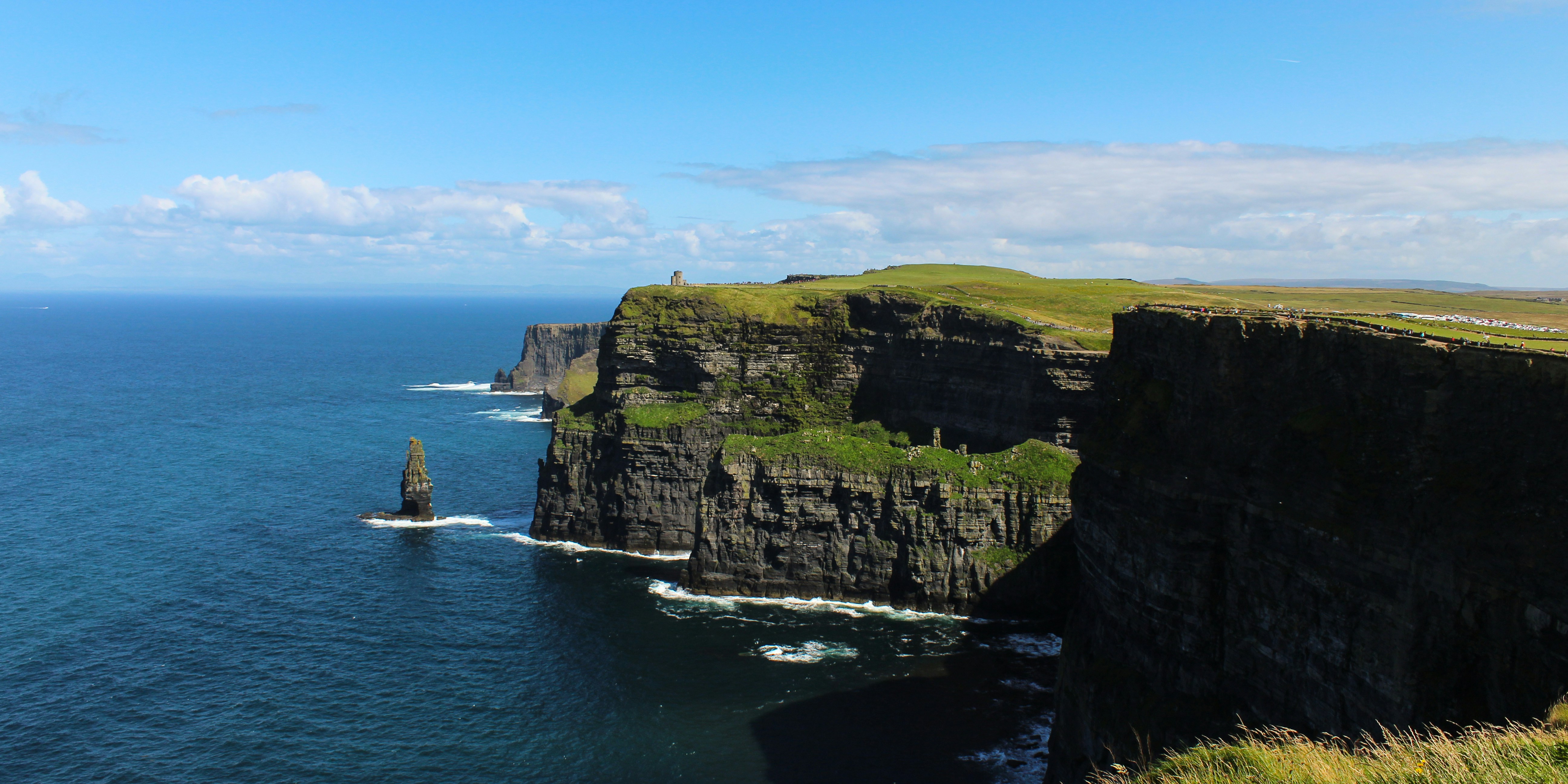Dramatic coastal cliffs meet the deep blue sea under a clear sky.