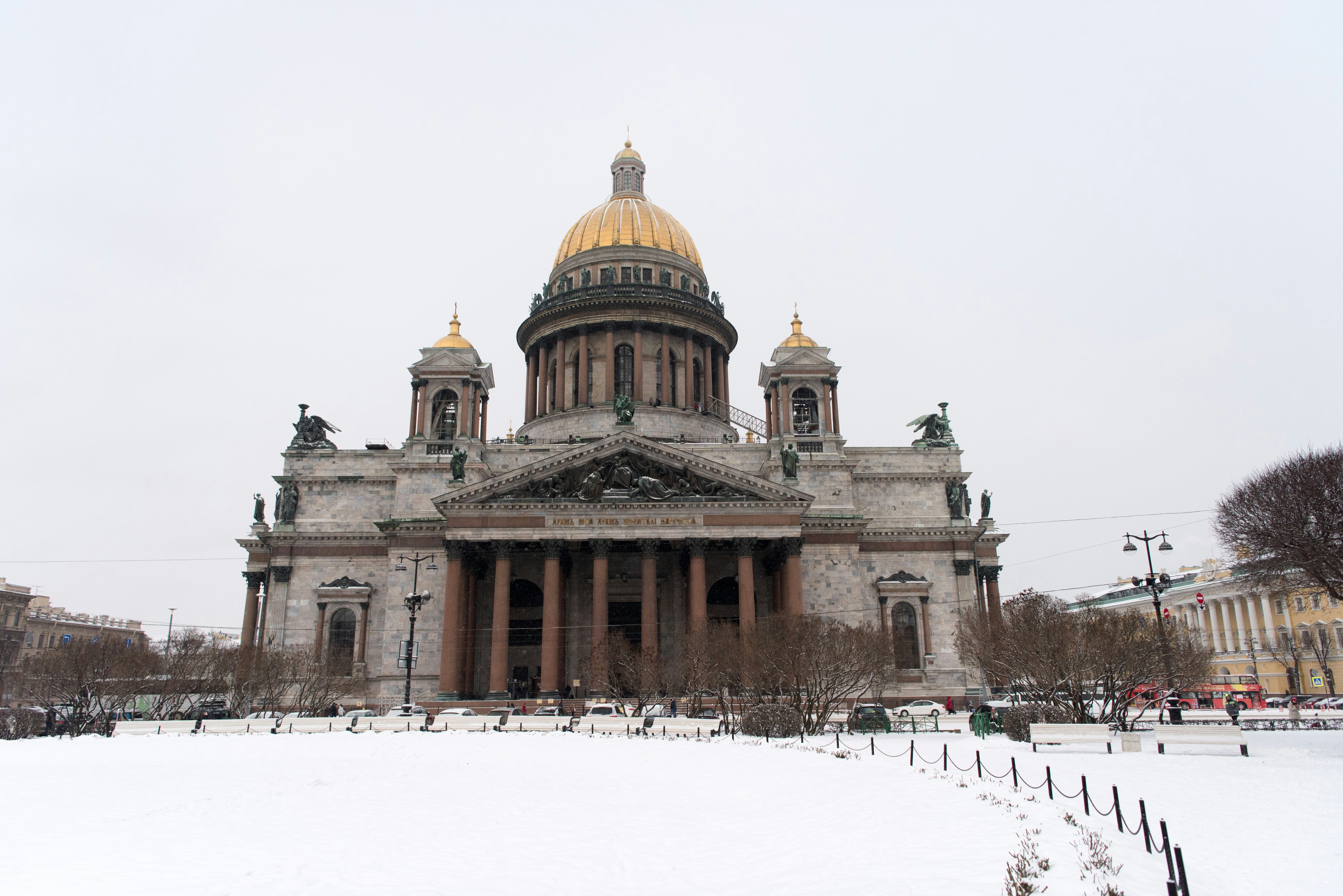 St. Isaac's Cathedral stands majestically in a snowy landscape, showcasing its grand architecture and golden dome. The scene captures the serene beauty of winter in the city.