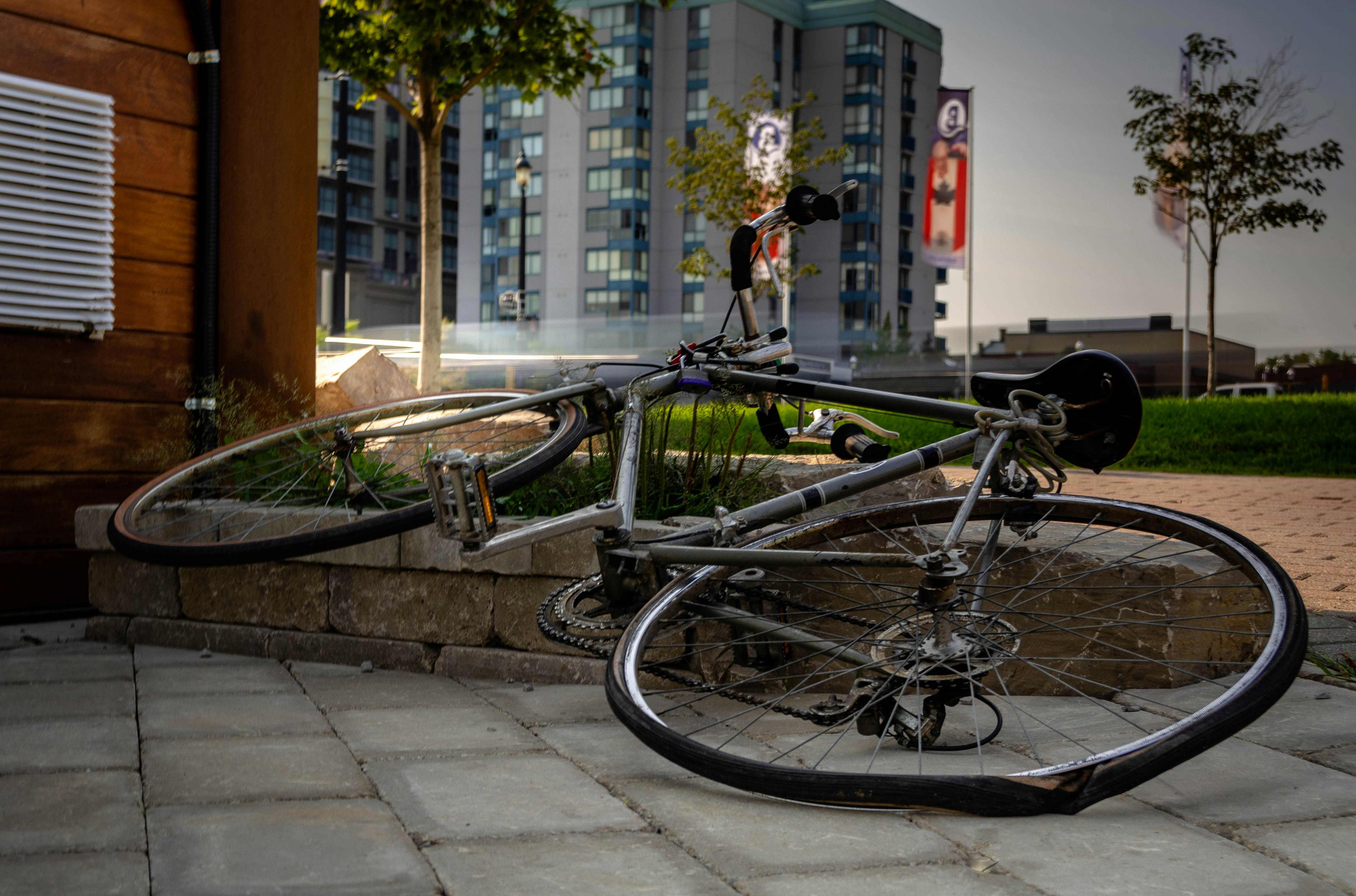 Battered bicycle lying on a modern city sidewalk as evening approaches.