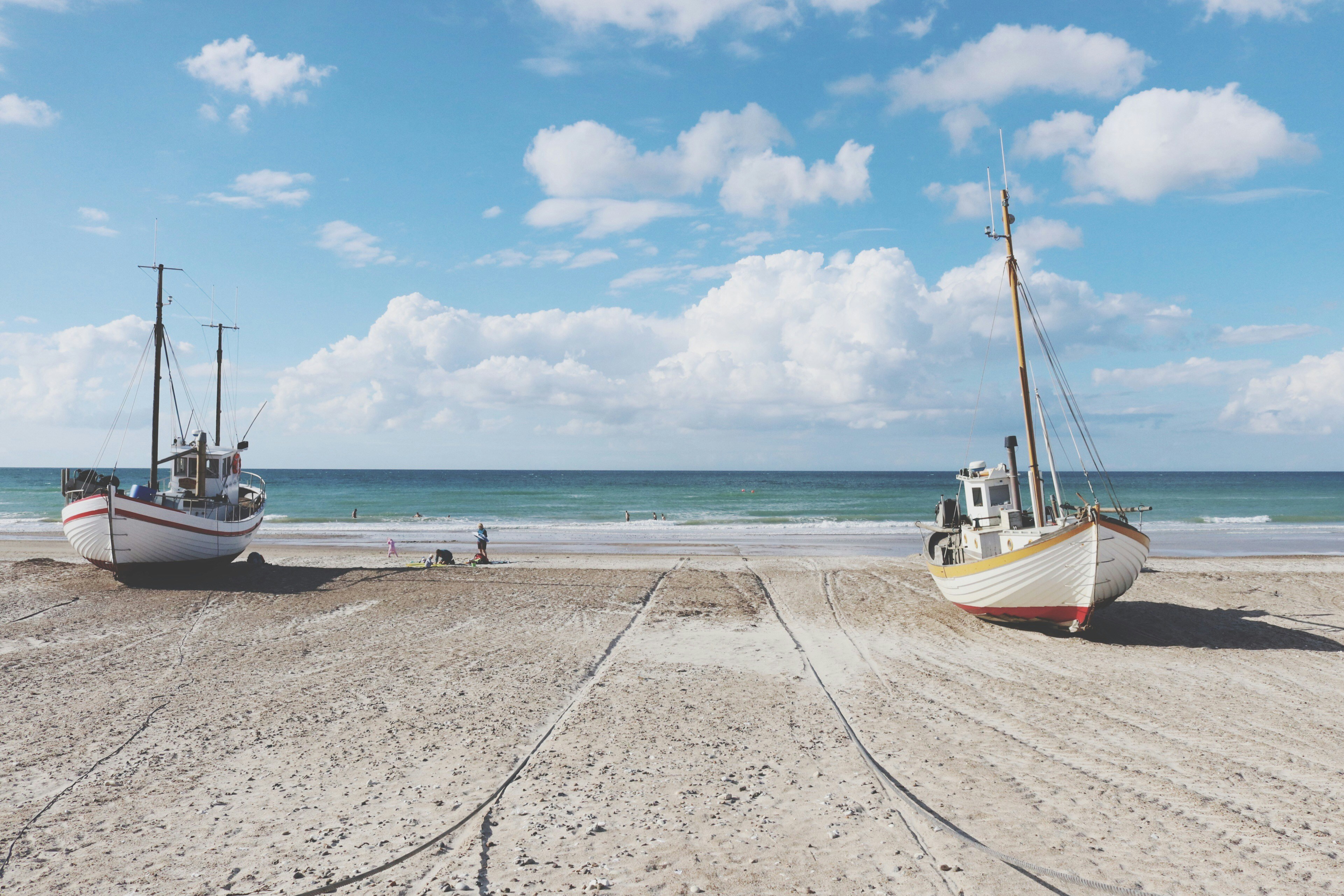 Two fishing boats resting on a sandy beach under a vibrant sky, with gentle waves lapping at the shore.